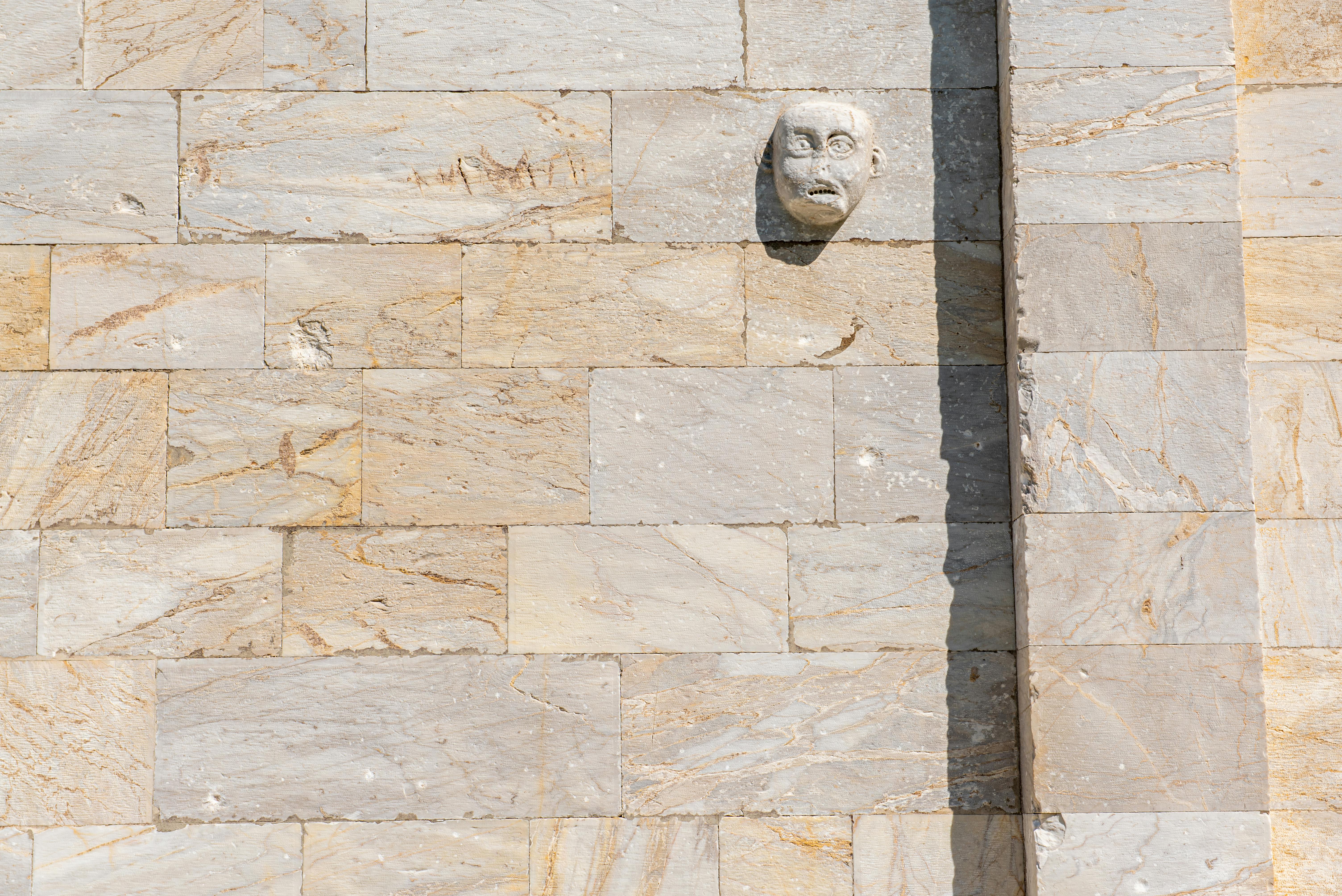 A Face Sculpture on Stone Wall · Free Stock Photo