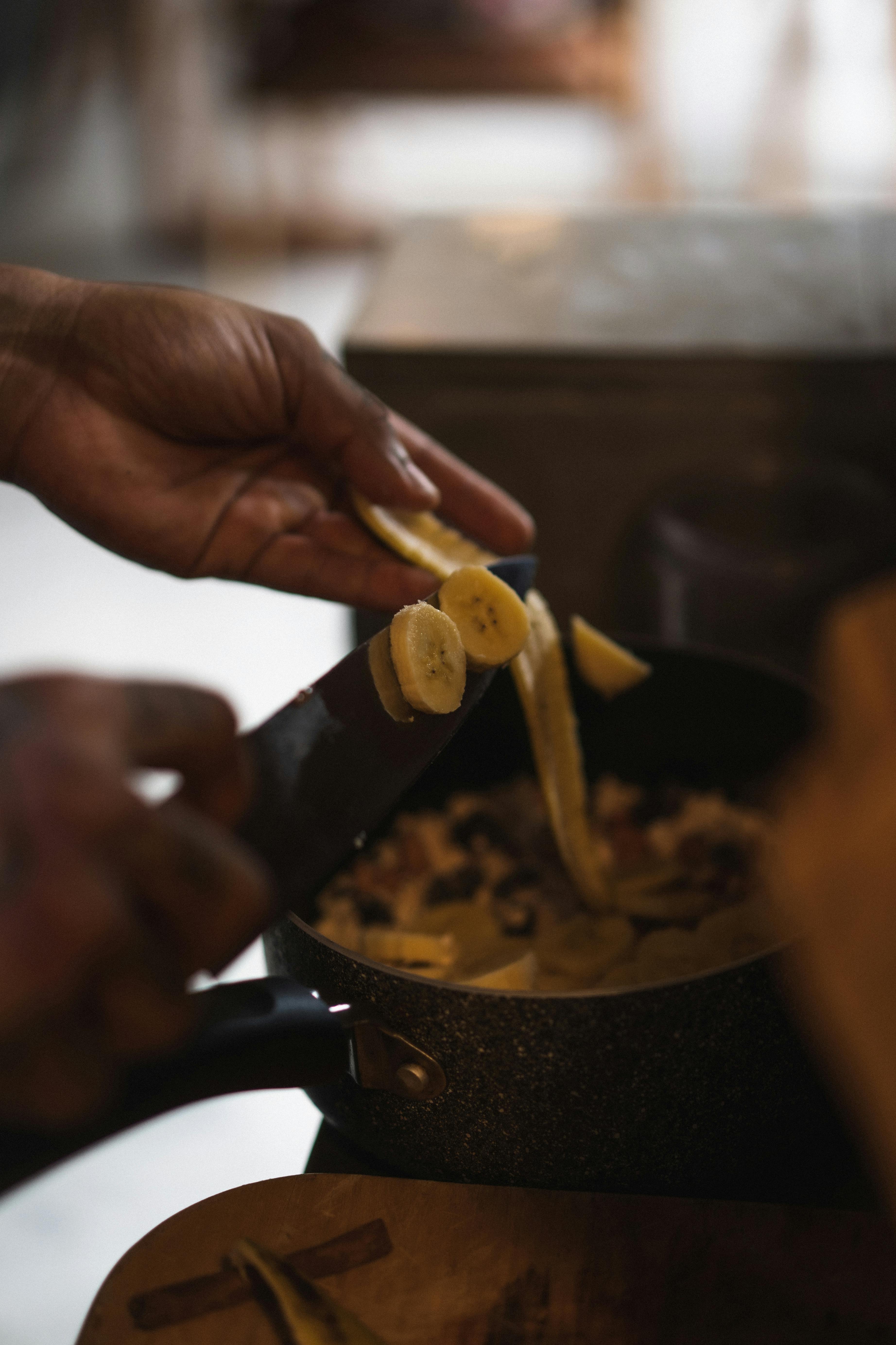 Close-up of Person Chopping a Banana into a Pan · Free Stock Photo