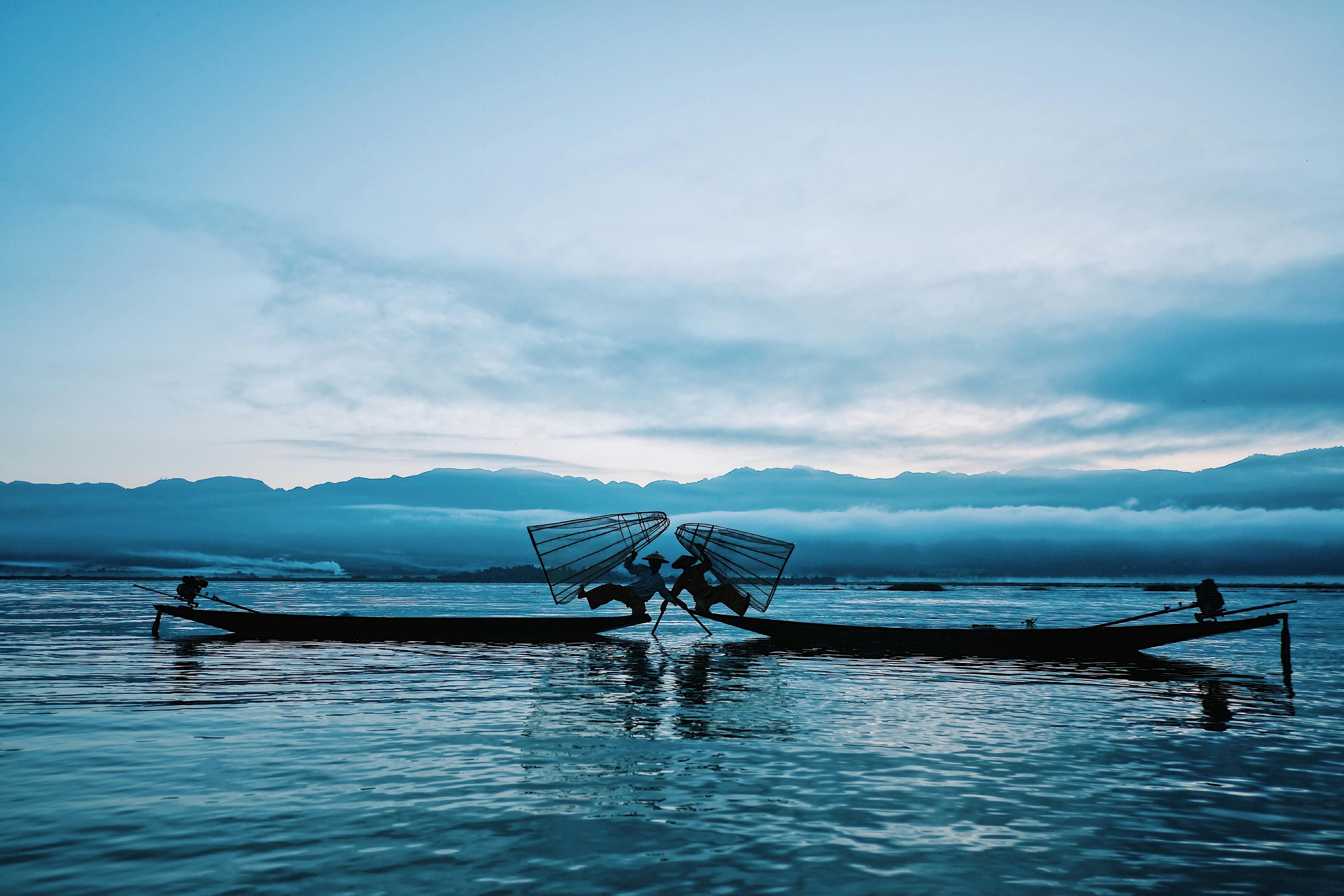 Silhouettes of Fishermen Holding Fish Nets · Free Stock Photo