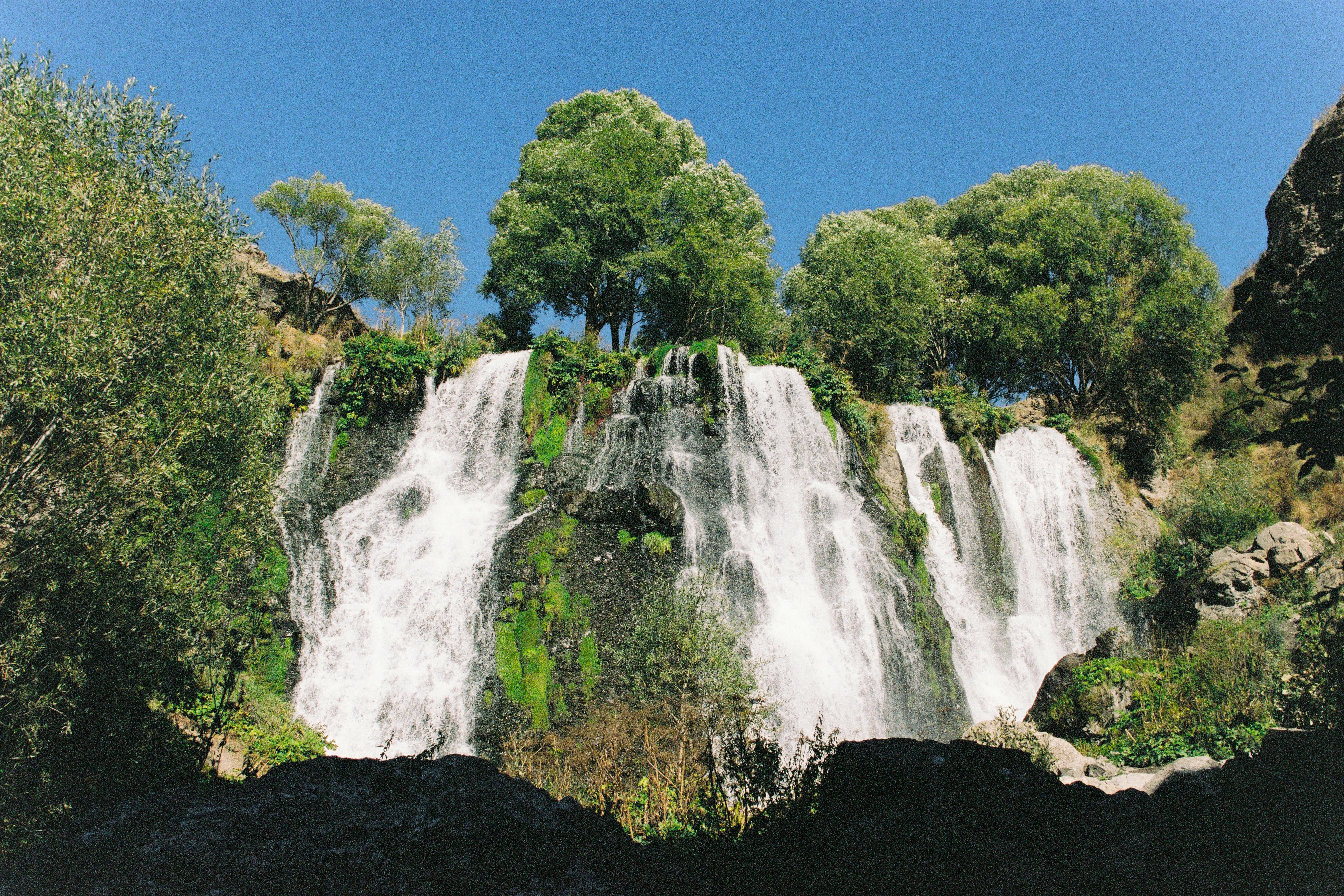 Low Angle Shot of Waterfalls Near Green Trees Under Blue Sky · Free ...