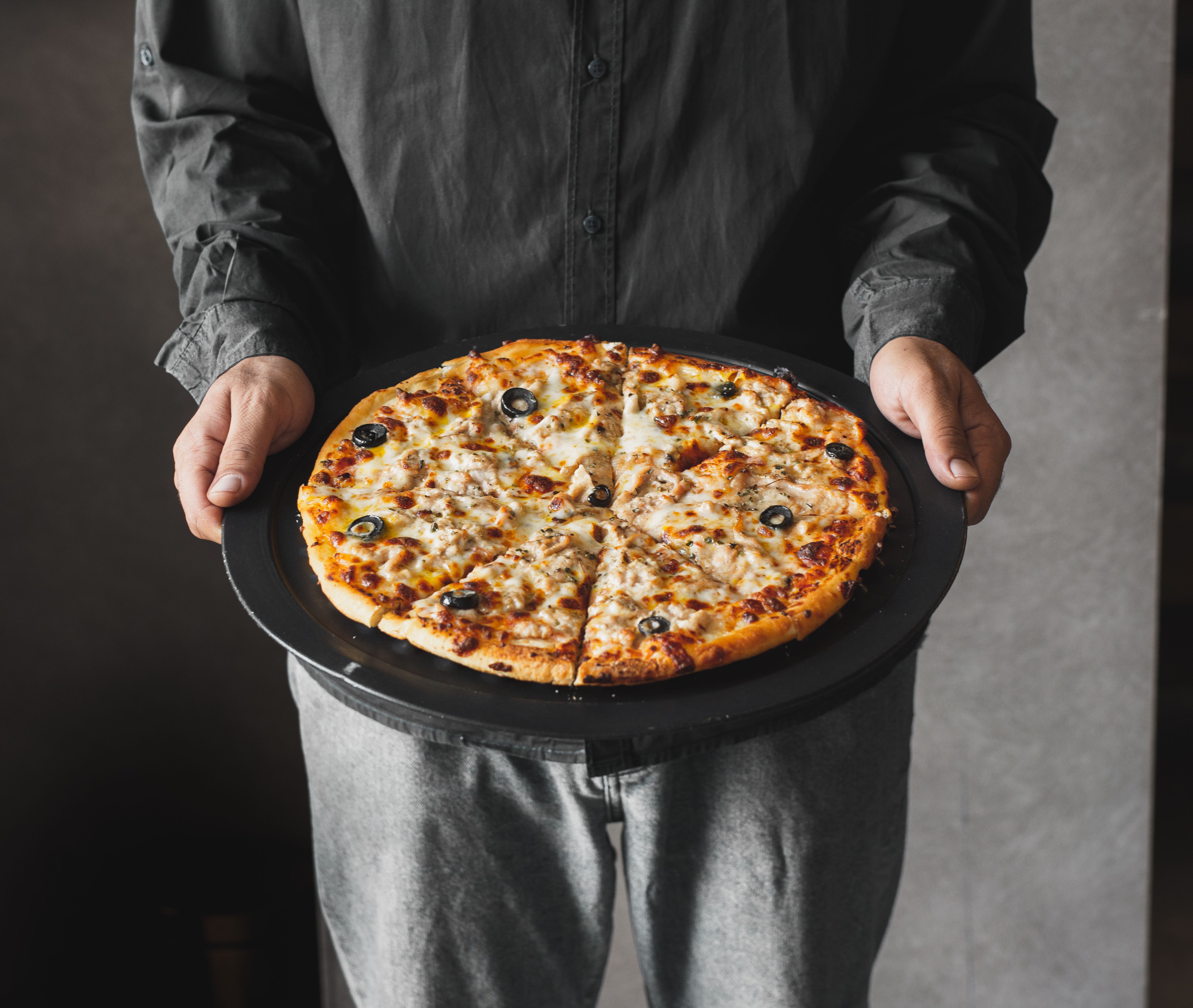 Person Holding a Pizza on a Tray · Free Stock Photo