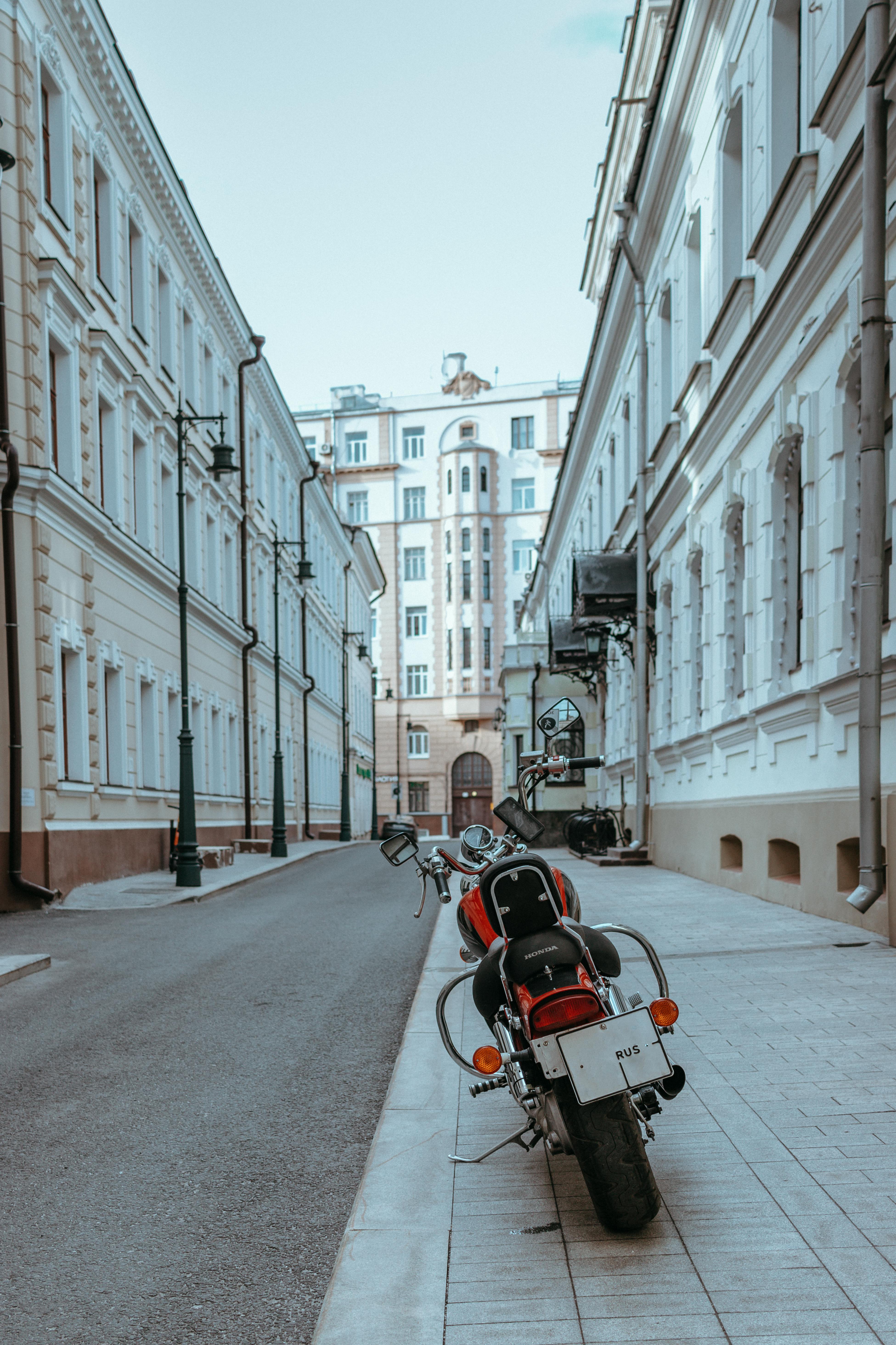 Motorcycle Parked on Sidewalk in Between Buildings · Free Stock Photo