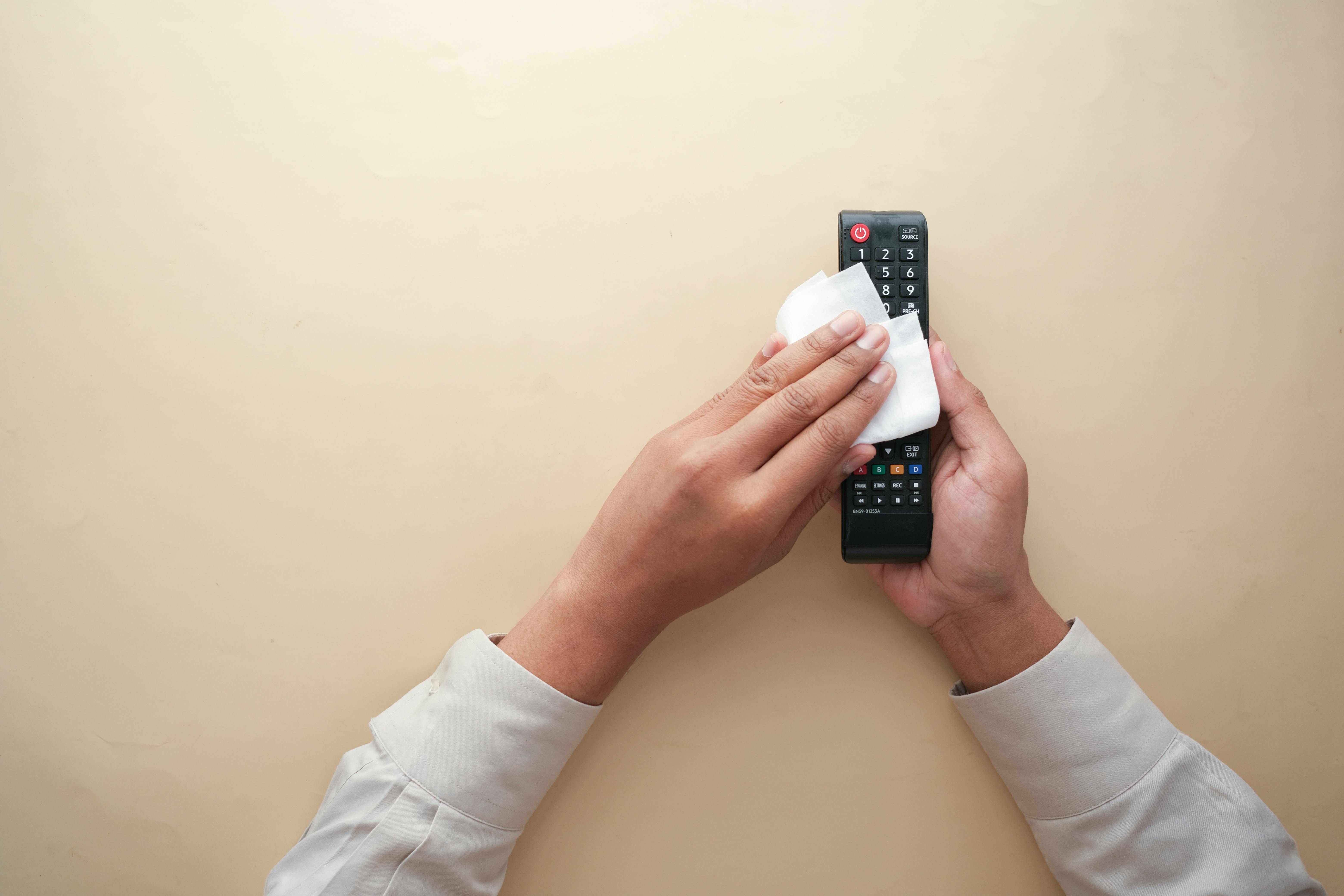 A Person Wiping the TV Remote · Free Stock Photo
