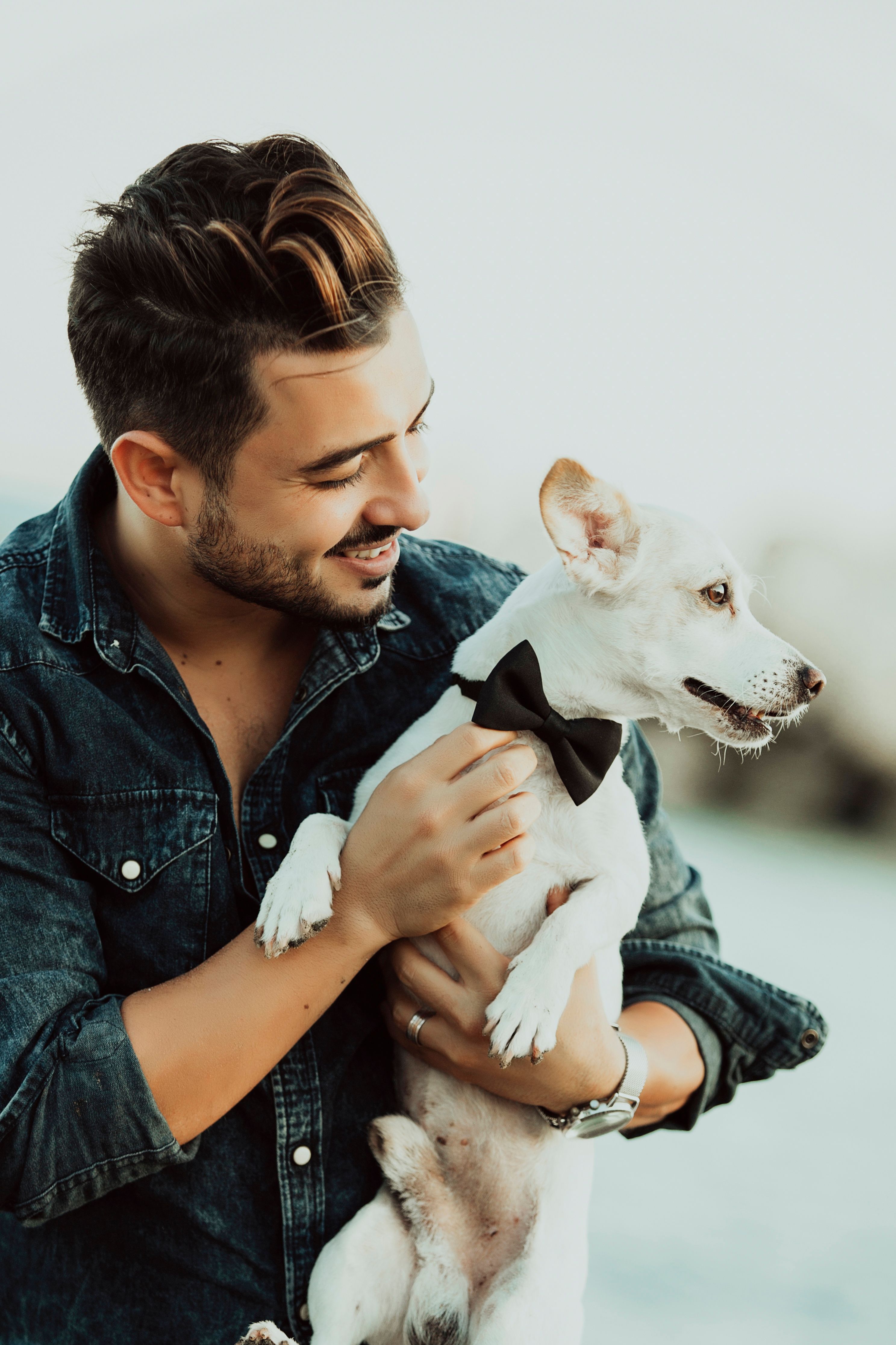 Photo of a Man Carrying a Dog with a Bowtie · Free Stock Photo