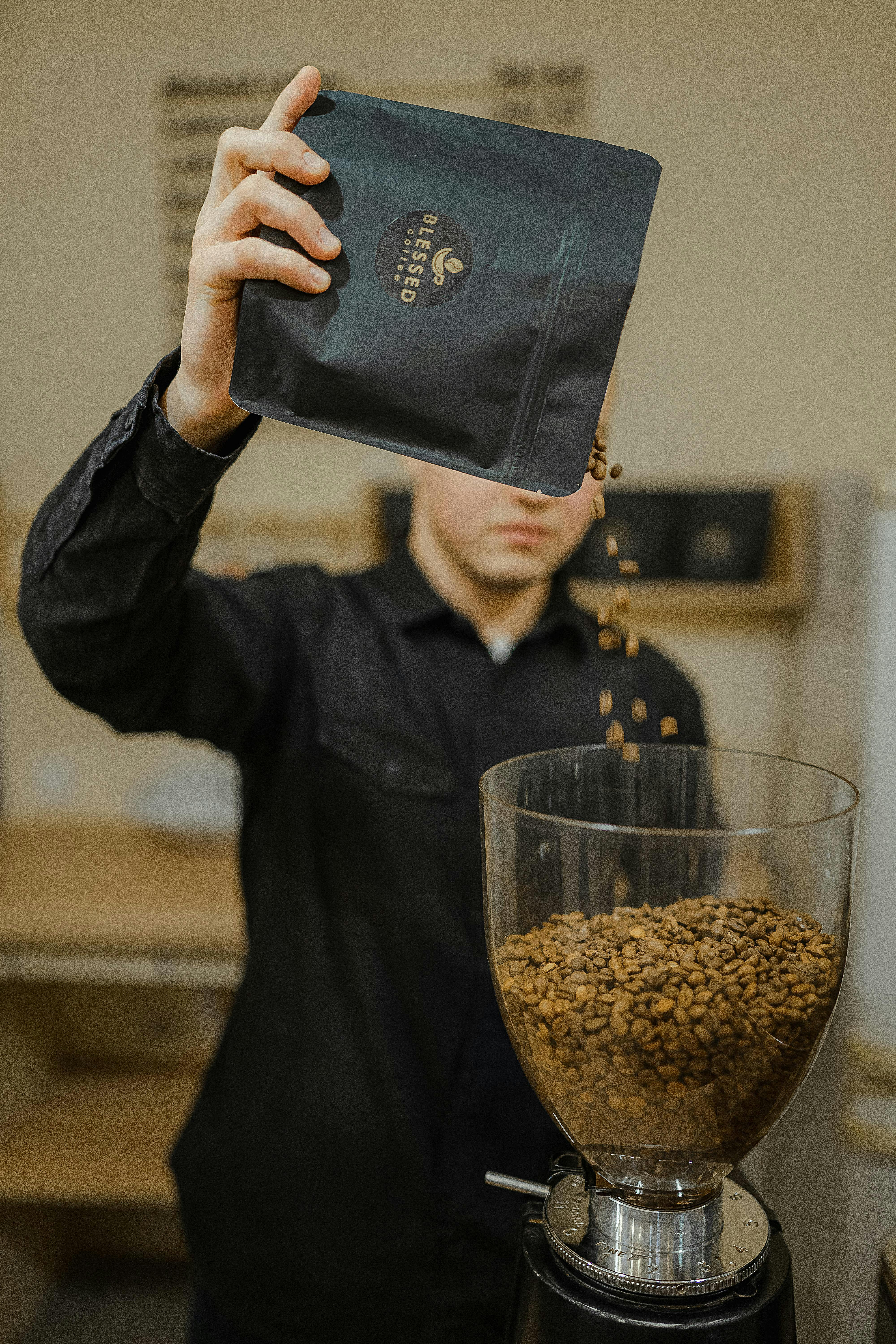 A Man in Black Long Sleeves Pouring Coffee Beans on a Coffee Maker ...