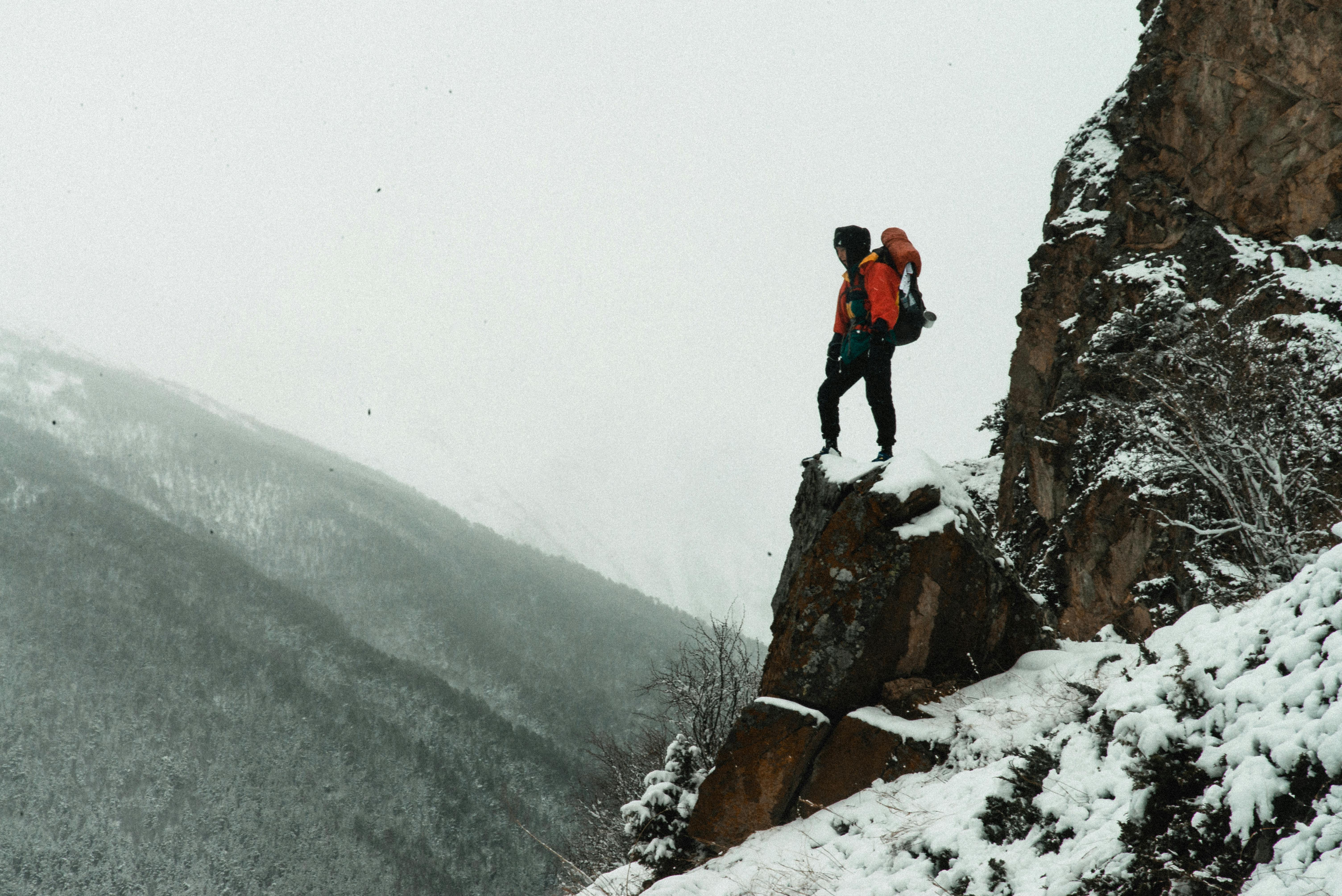 Man in Red Jacket Standing on Rocky Mountain · Free Stock Photo