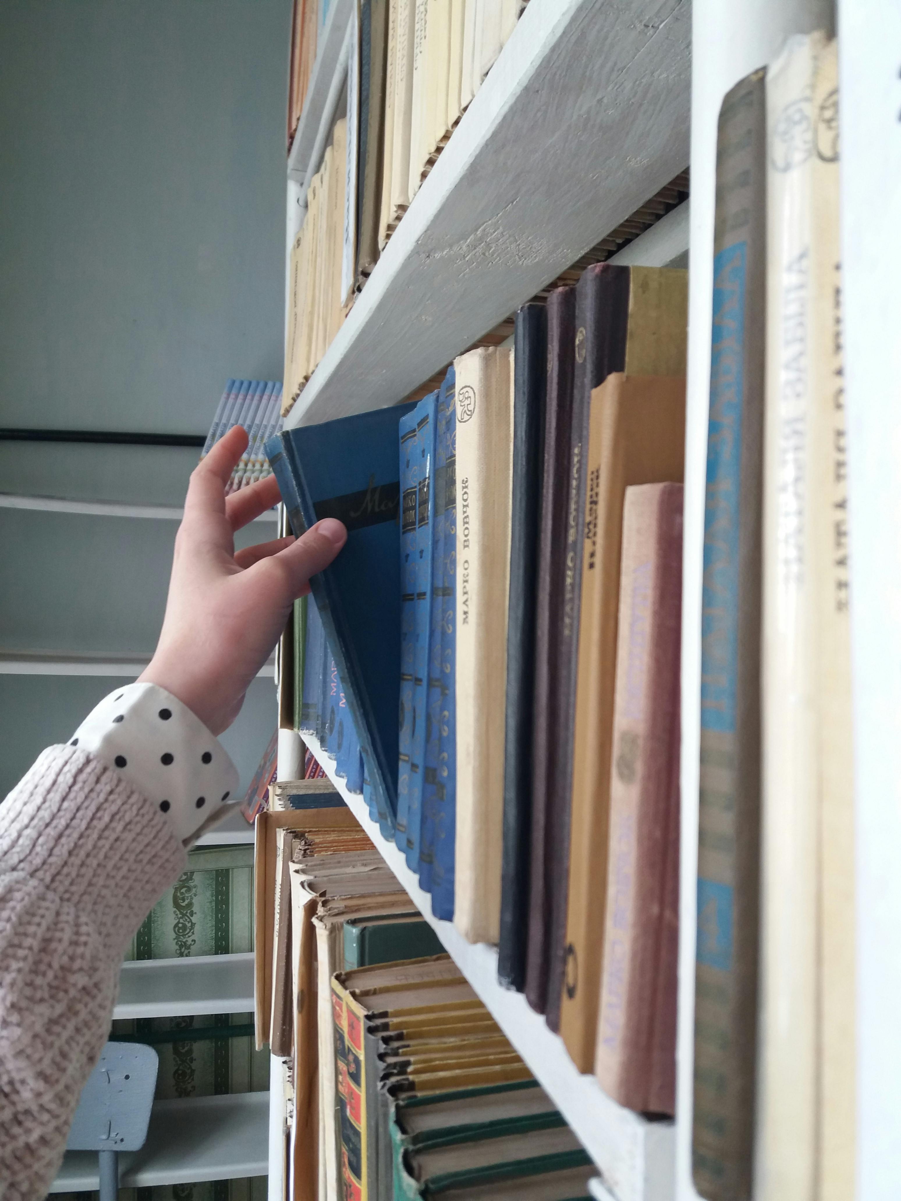 Man Getting a Book from a Bookcase · Free Stock Photo