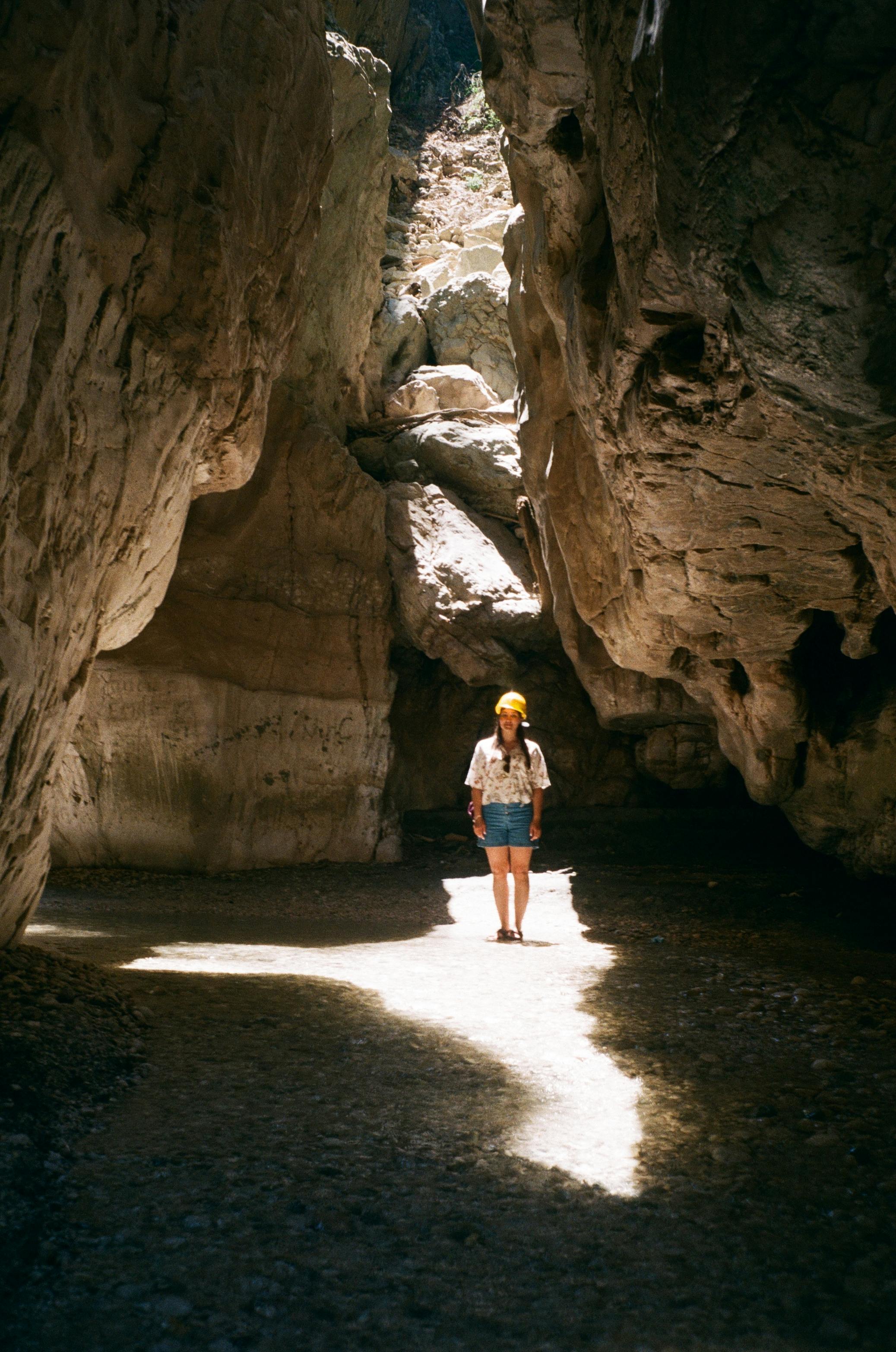 A Woman Wearing a Hard Hat Standing under Rock Formations · Free Stock ...
