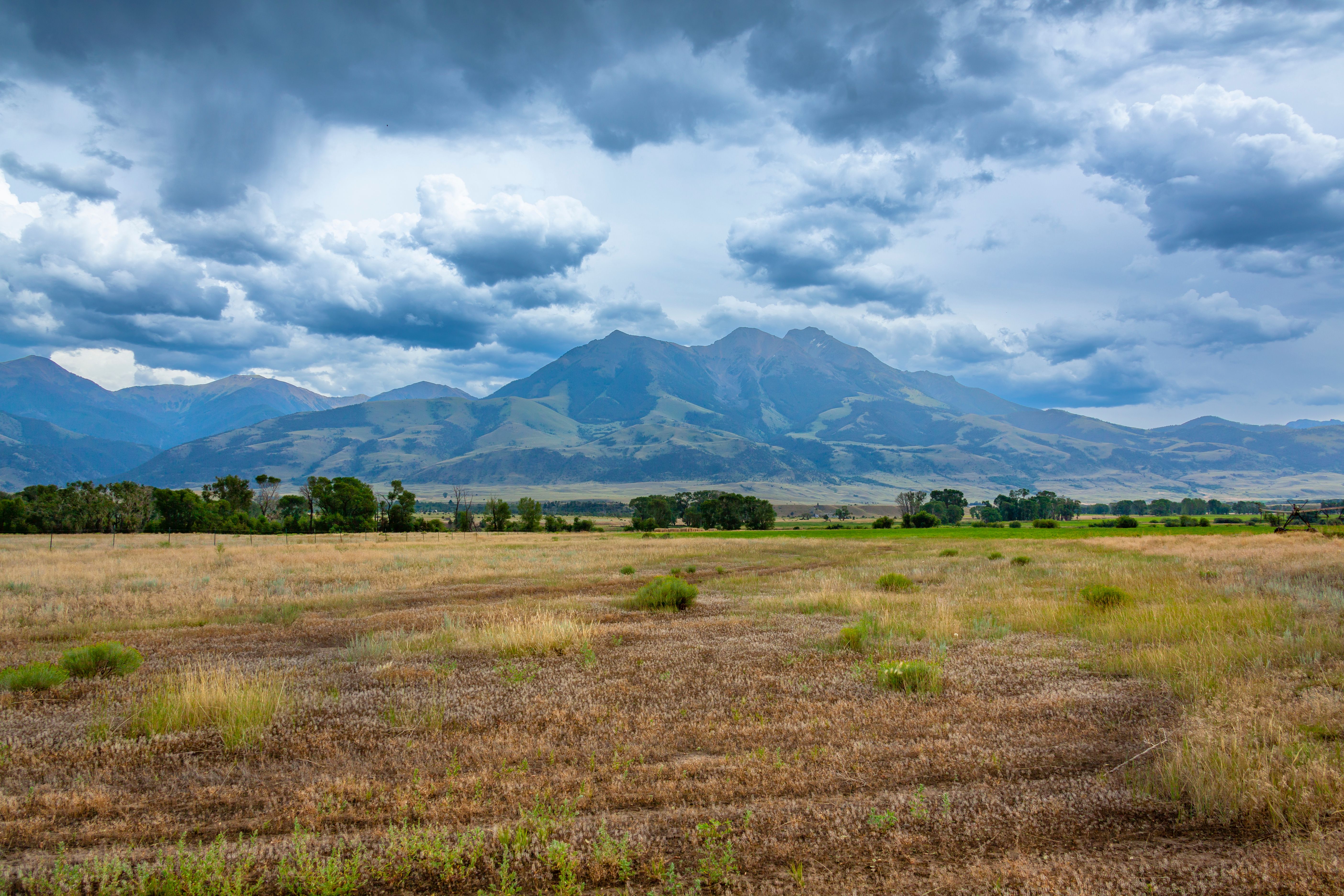 Scenic View of Grassland near Mountains under Cloudy Sky · Free Stock Photo