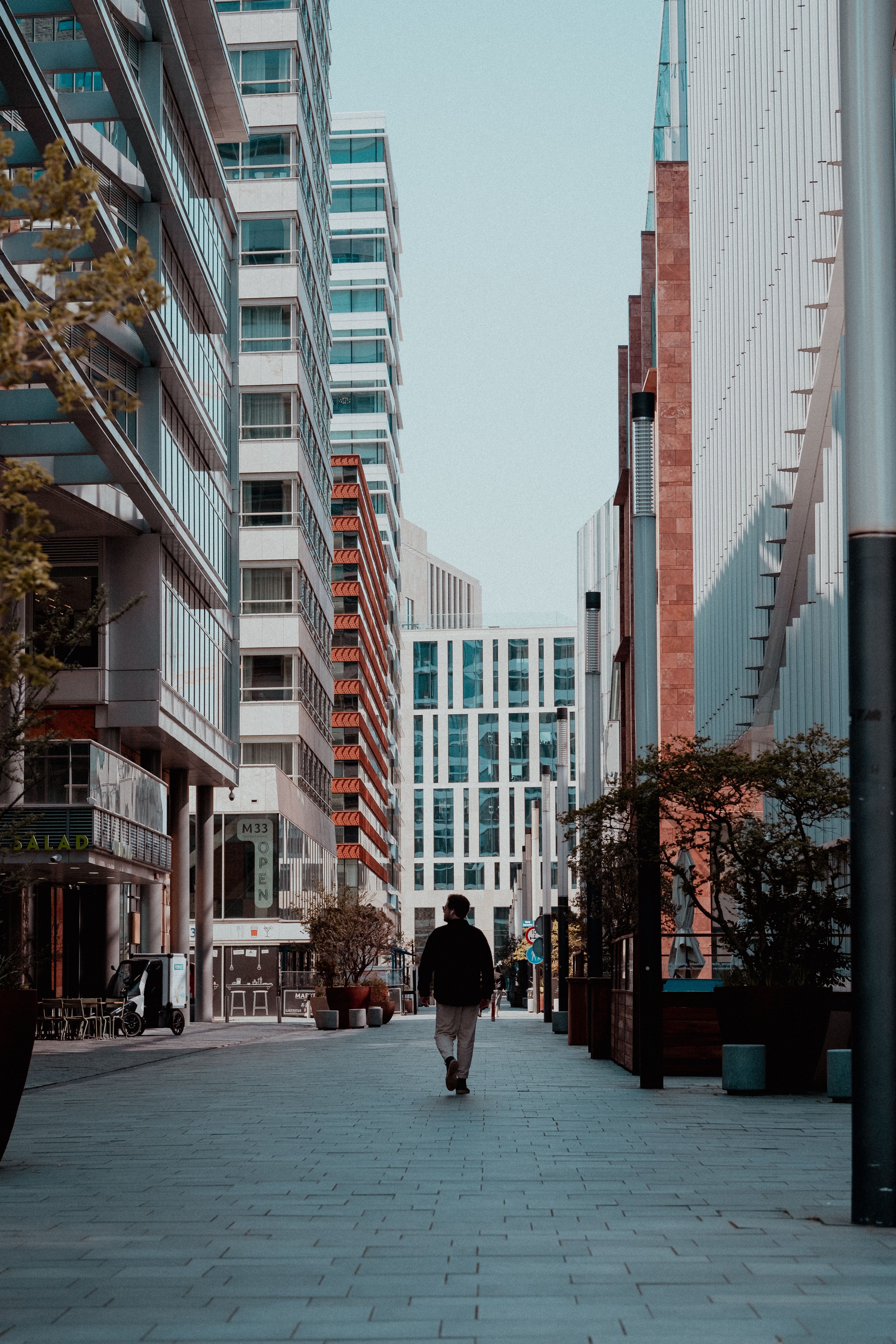 Man Walking on the Street Between High Rise Buildings · Free Stock Photo