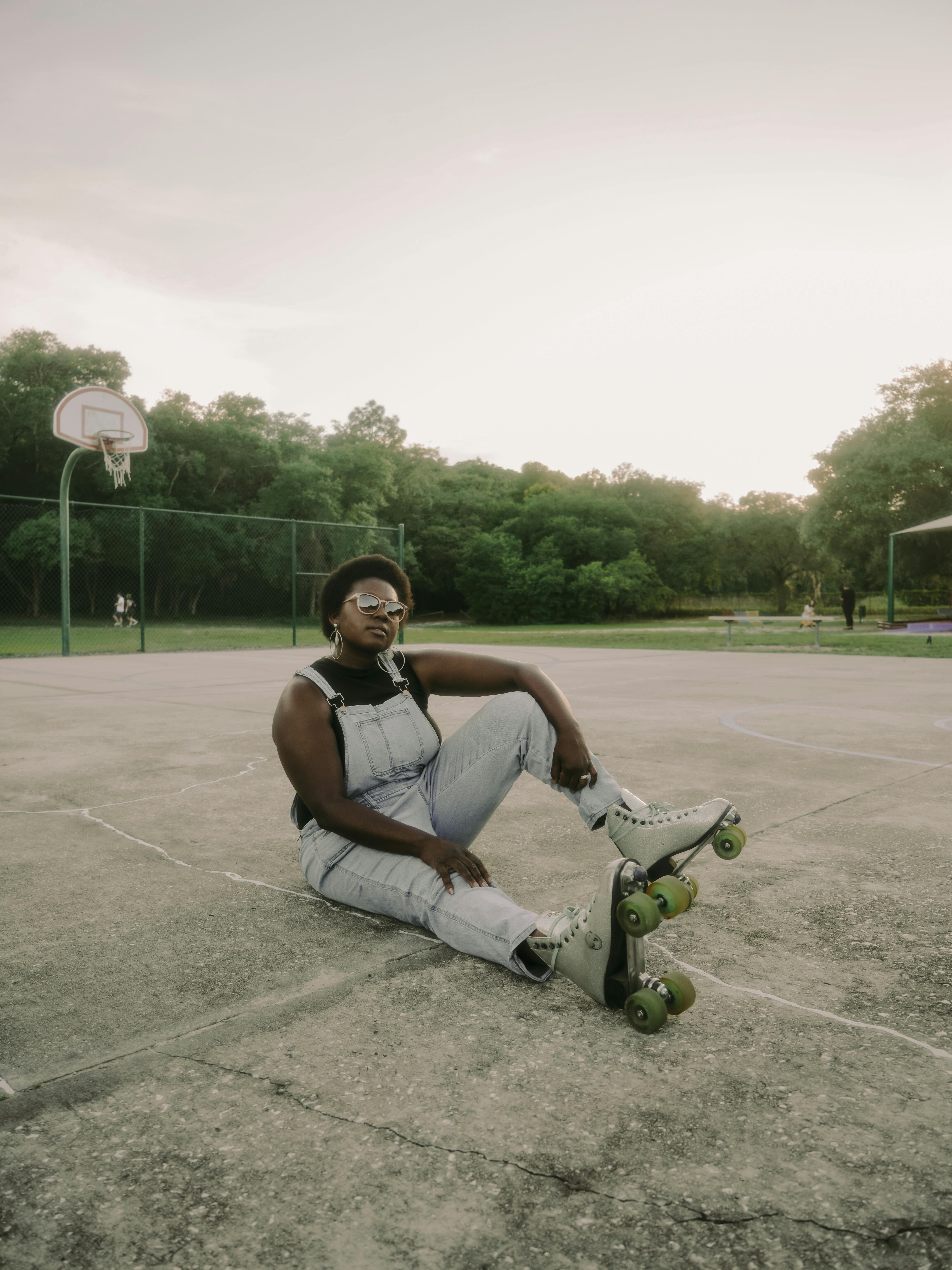 Woman Sitting on Basketball Court with Roller Skates · Free Stock Photo