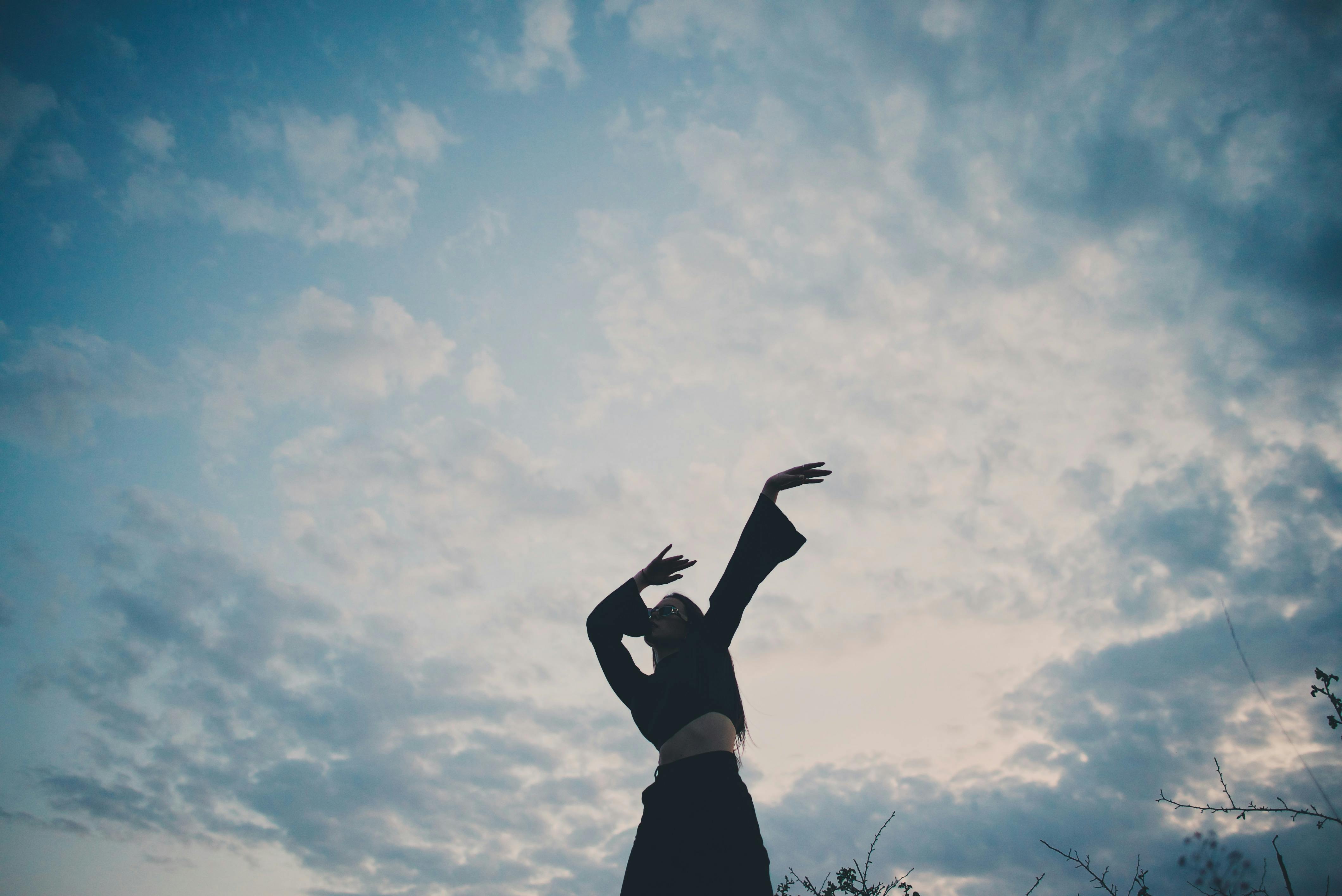 Hands Raised Up Towards Overcast Sky with Rainbow · Free Stock Photo