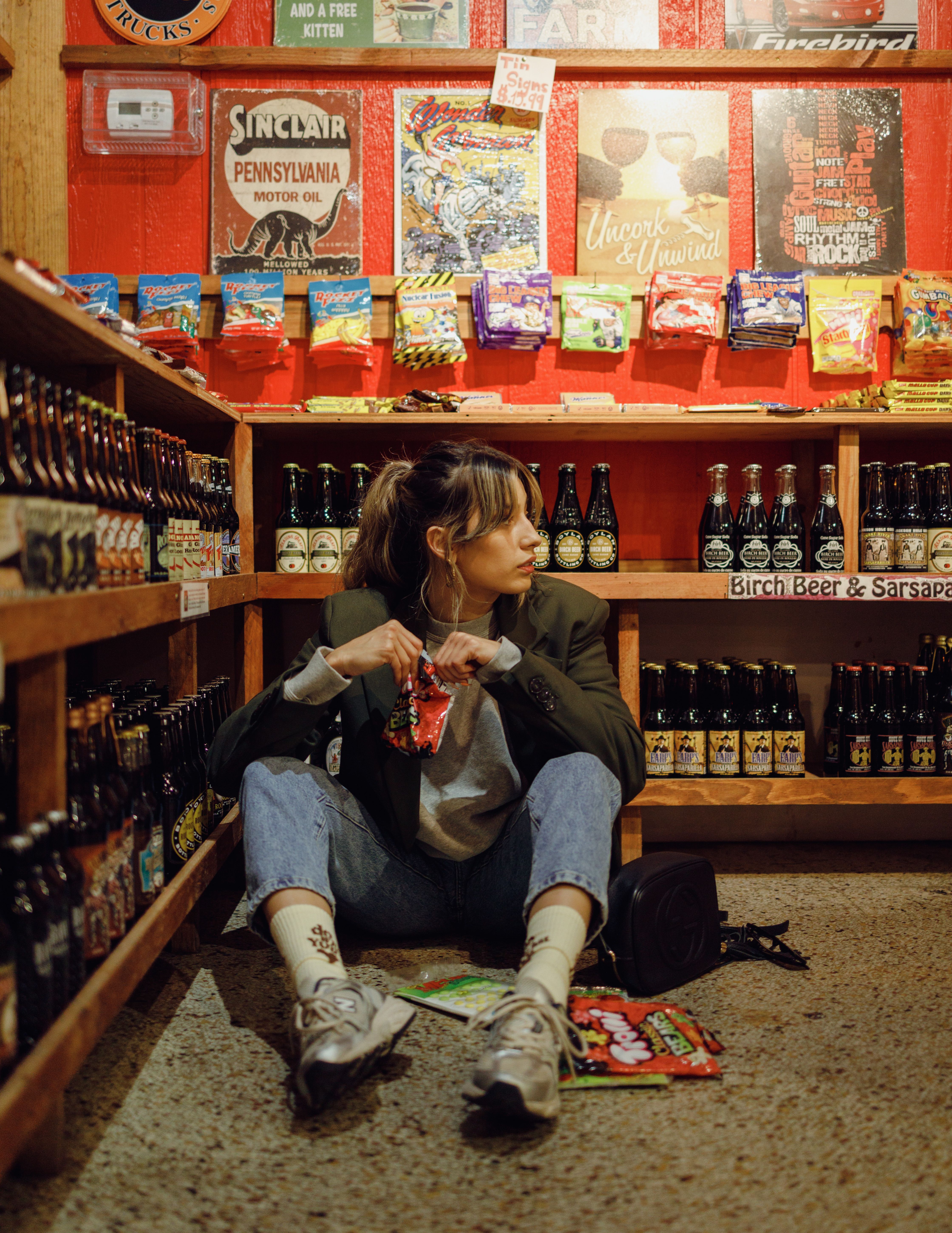 A Woman Sitting on the Floor in Front of Beer Shelves · Free Stock Photo