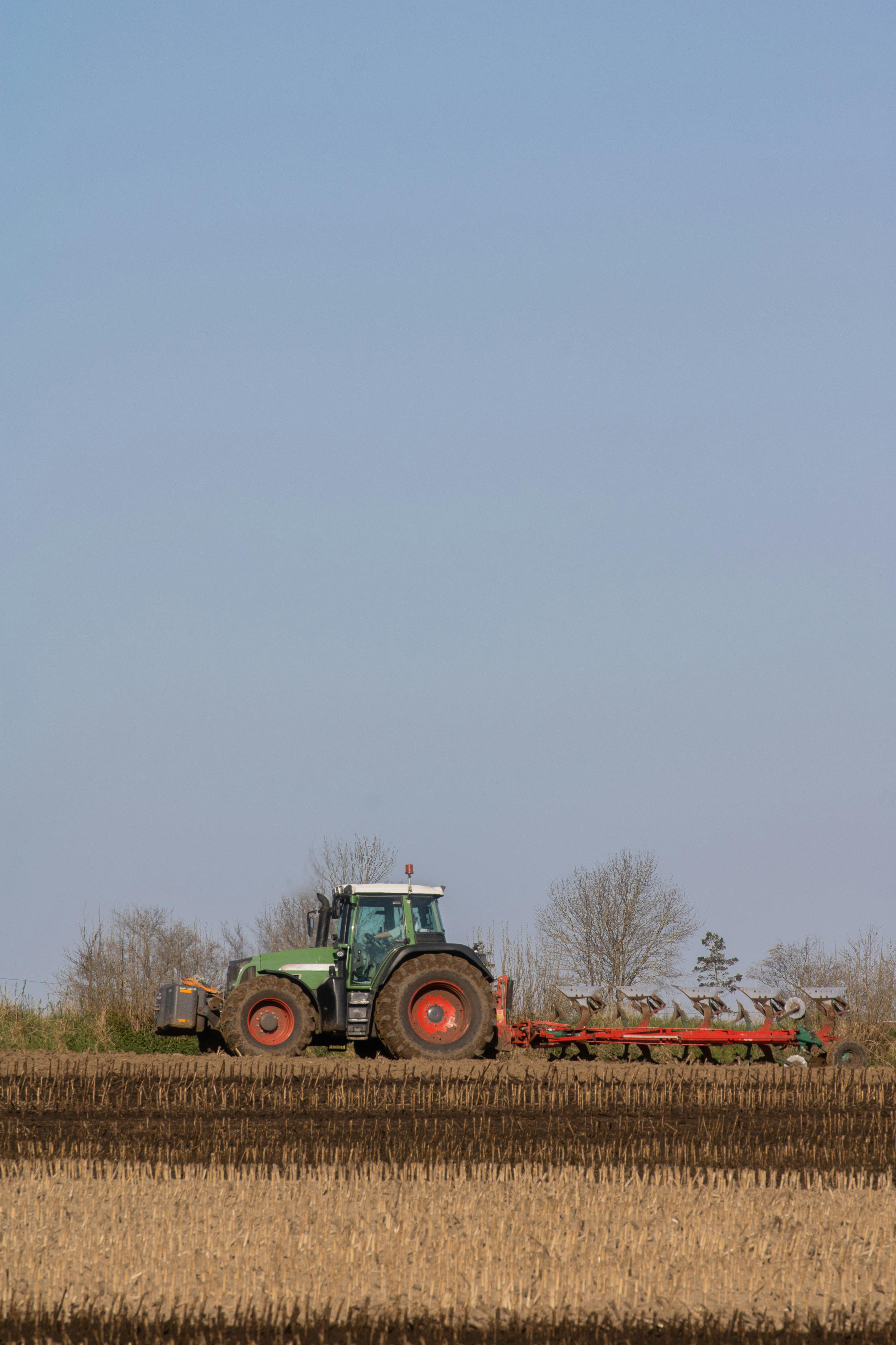Orange and Black Tractor Next to Piles of Rocks · Free Stock Photo