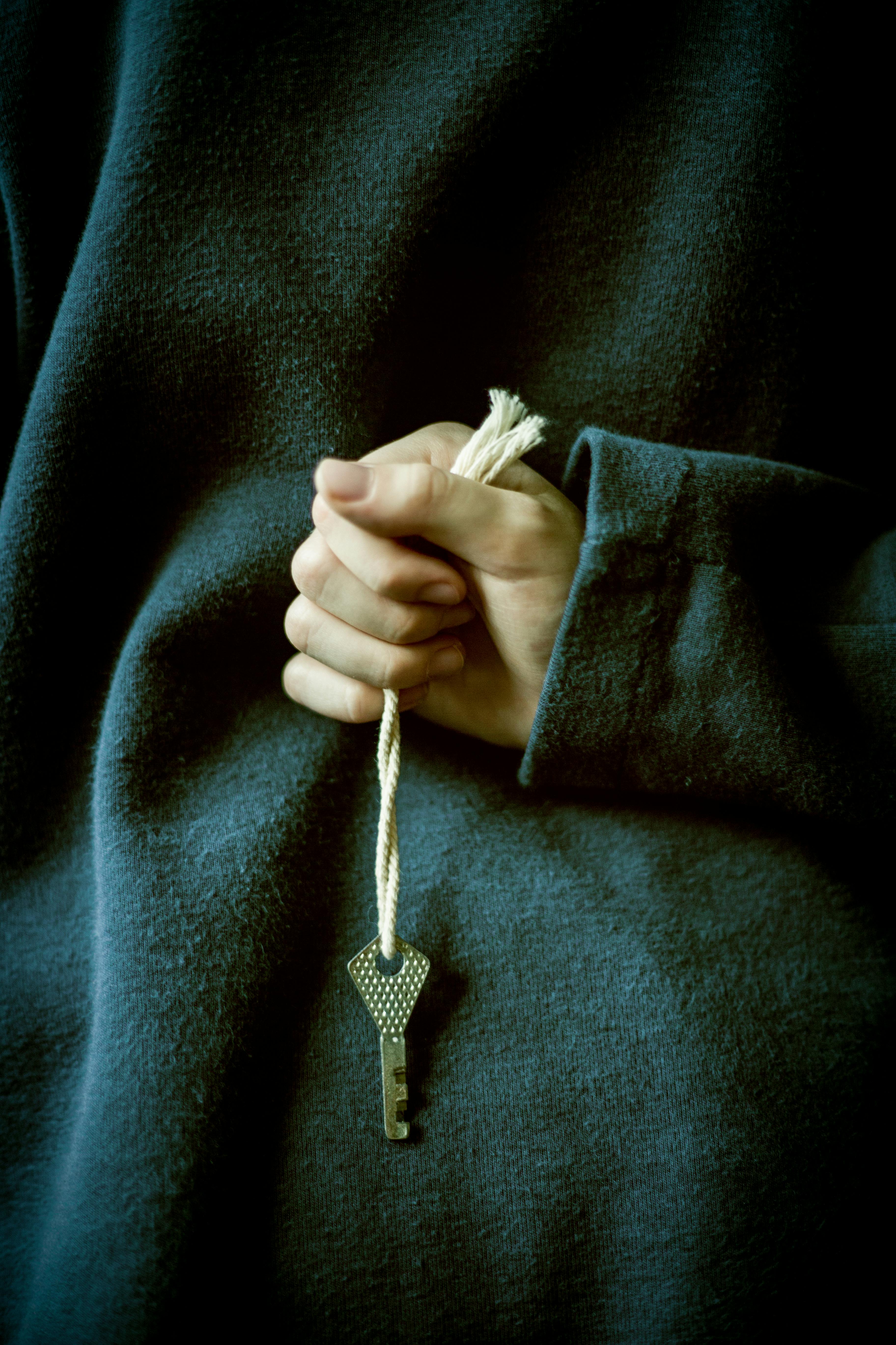 Close-up of Person Holding a Key Behind Their Back · Free Stock Photo
