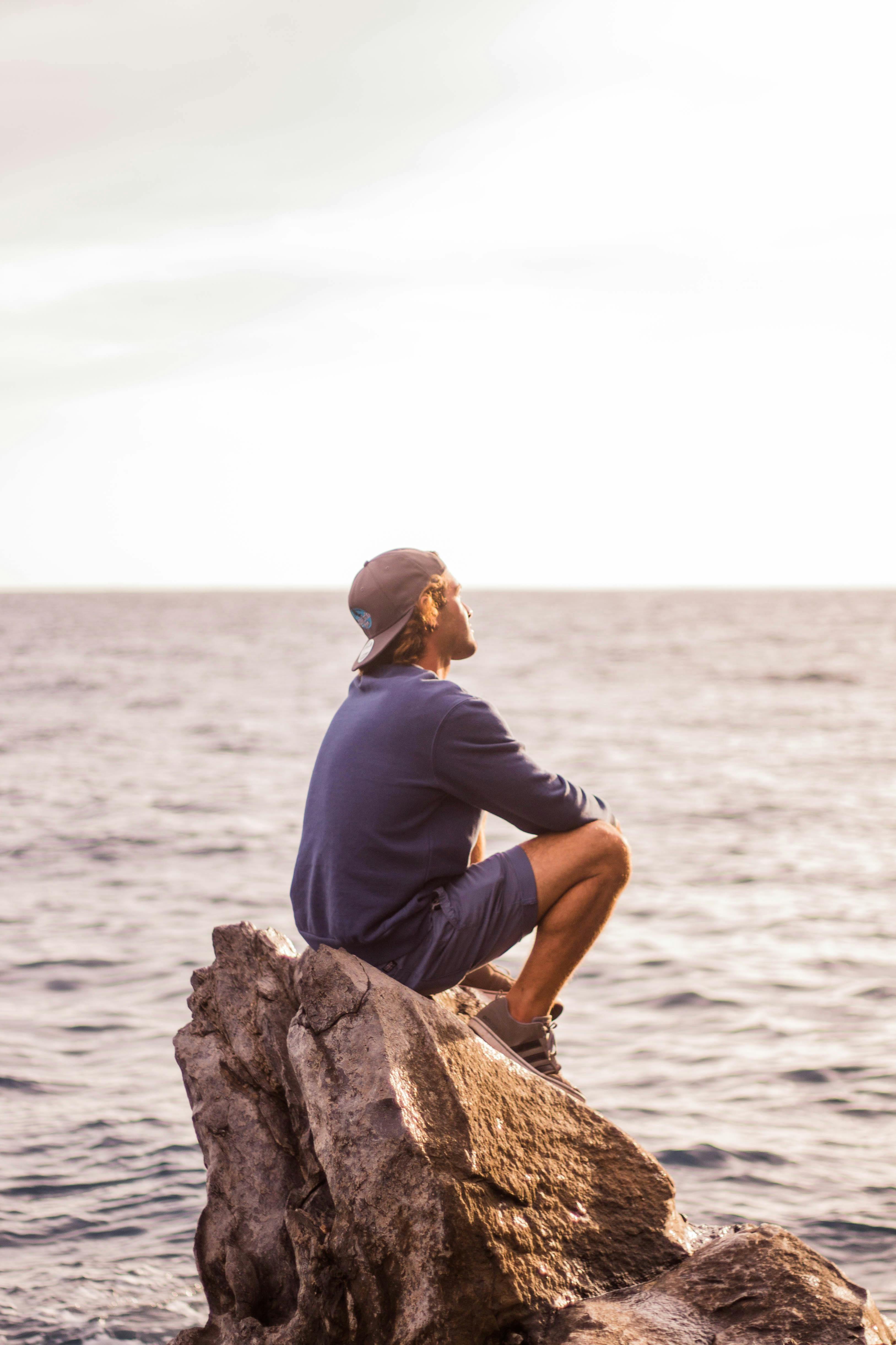 A Side View of a Man Wearing a Cap, Sitting and Looking at the Sea ...