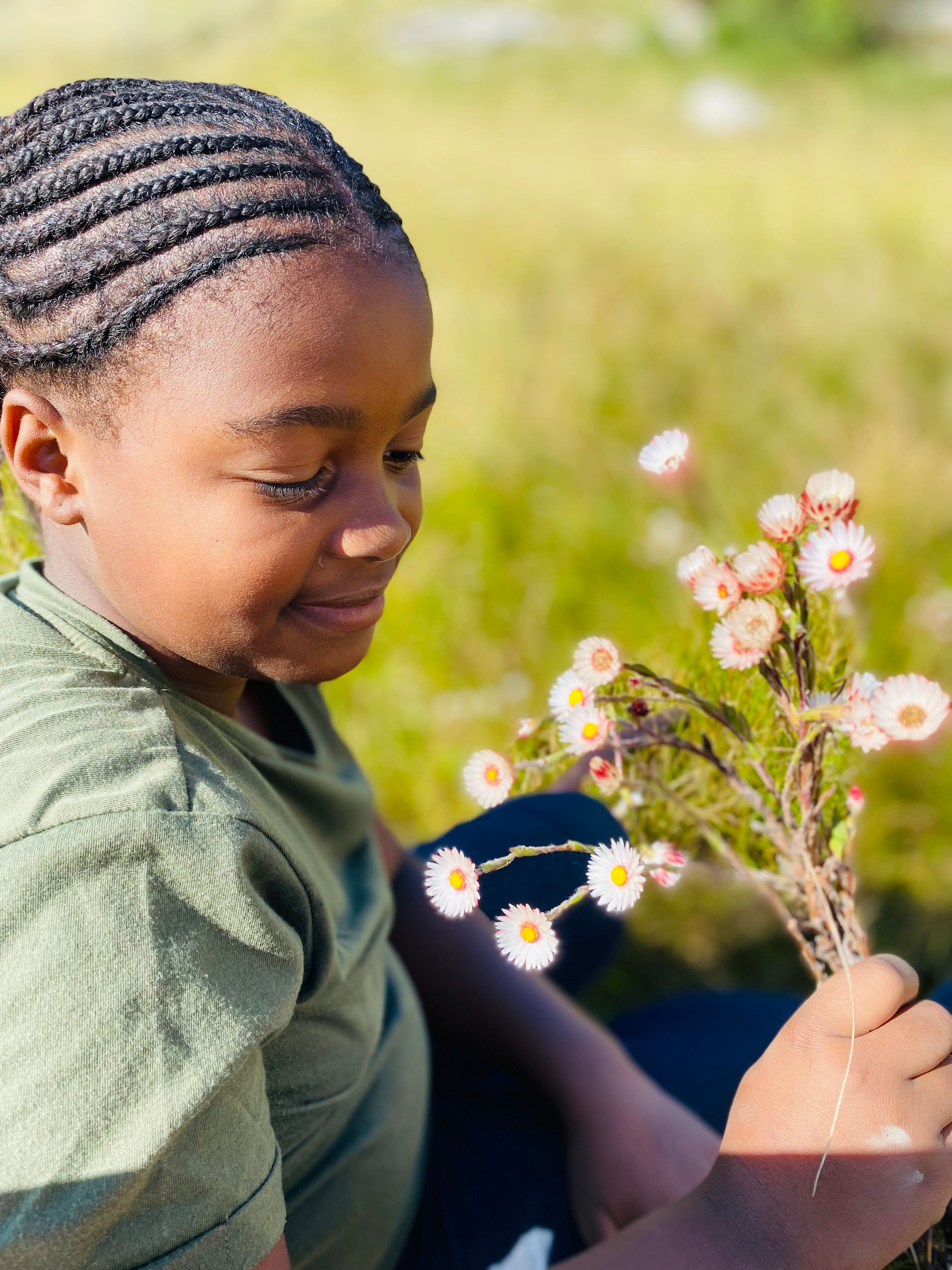 Photo of a Smiling Black Child Holding a Bunch of Daisies · Free Stock ...