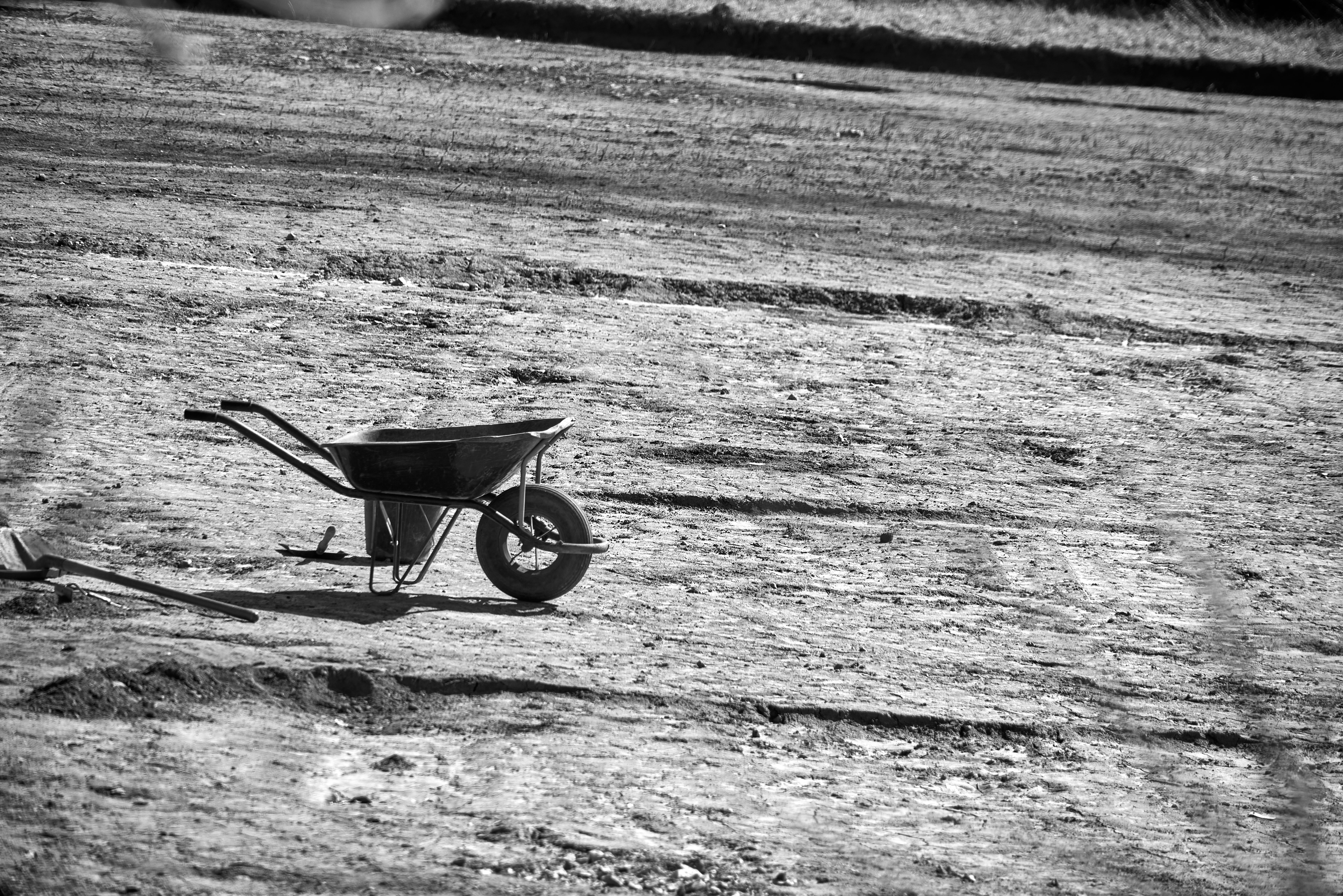 Grayscale Photo of a Wheelbarrow on the Ground · Free Stock Photo