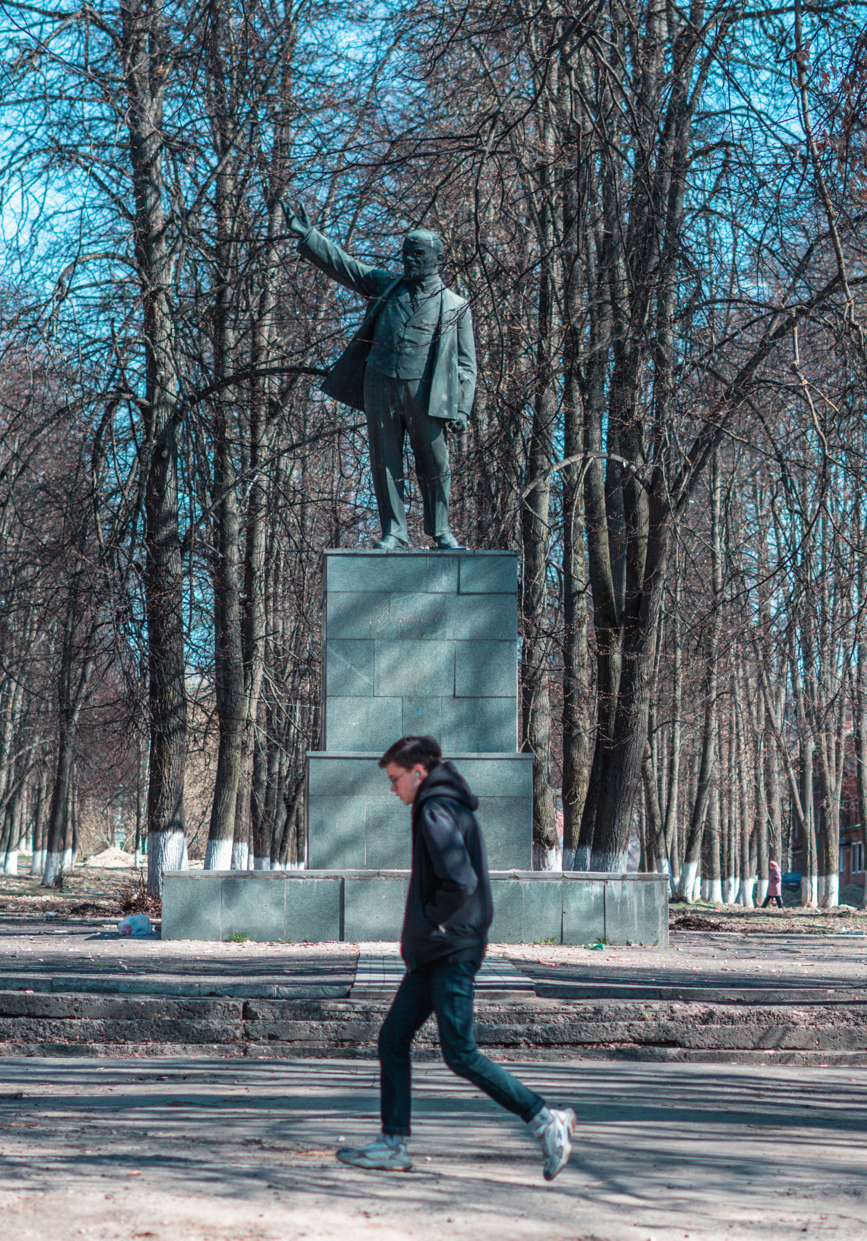Young Man Passing By a Statue in a Park · Free Stock Photo