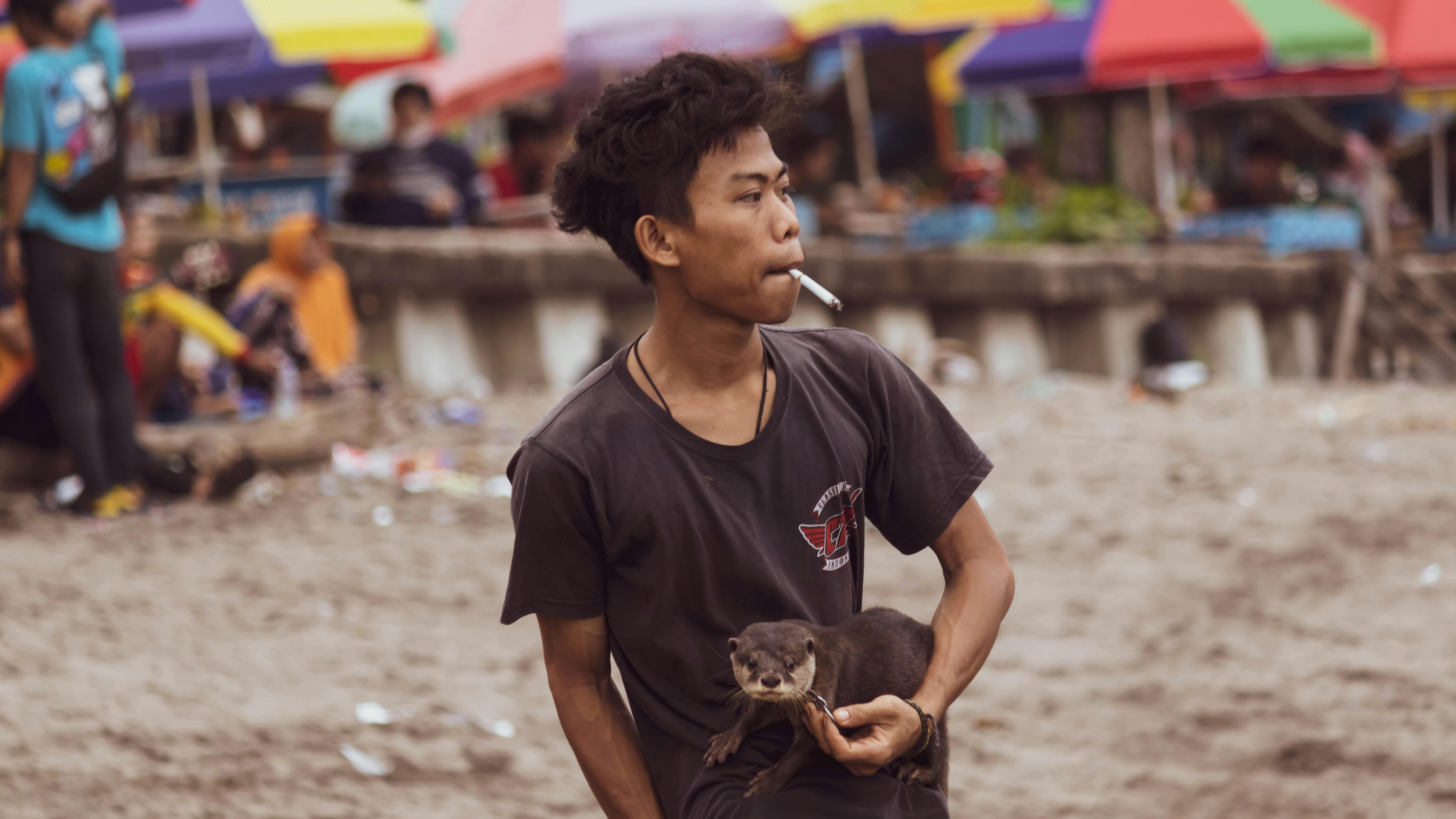 Young Man Holding an Otter and Smoking a Cigarette · Free Stock Photo