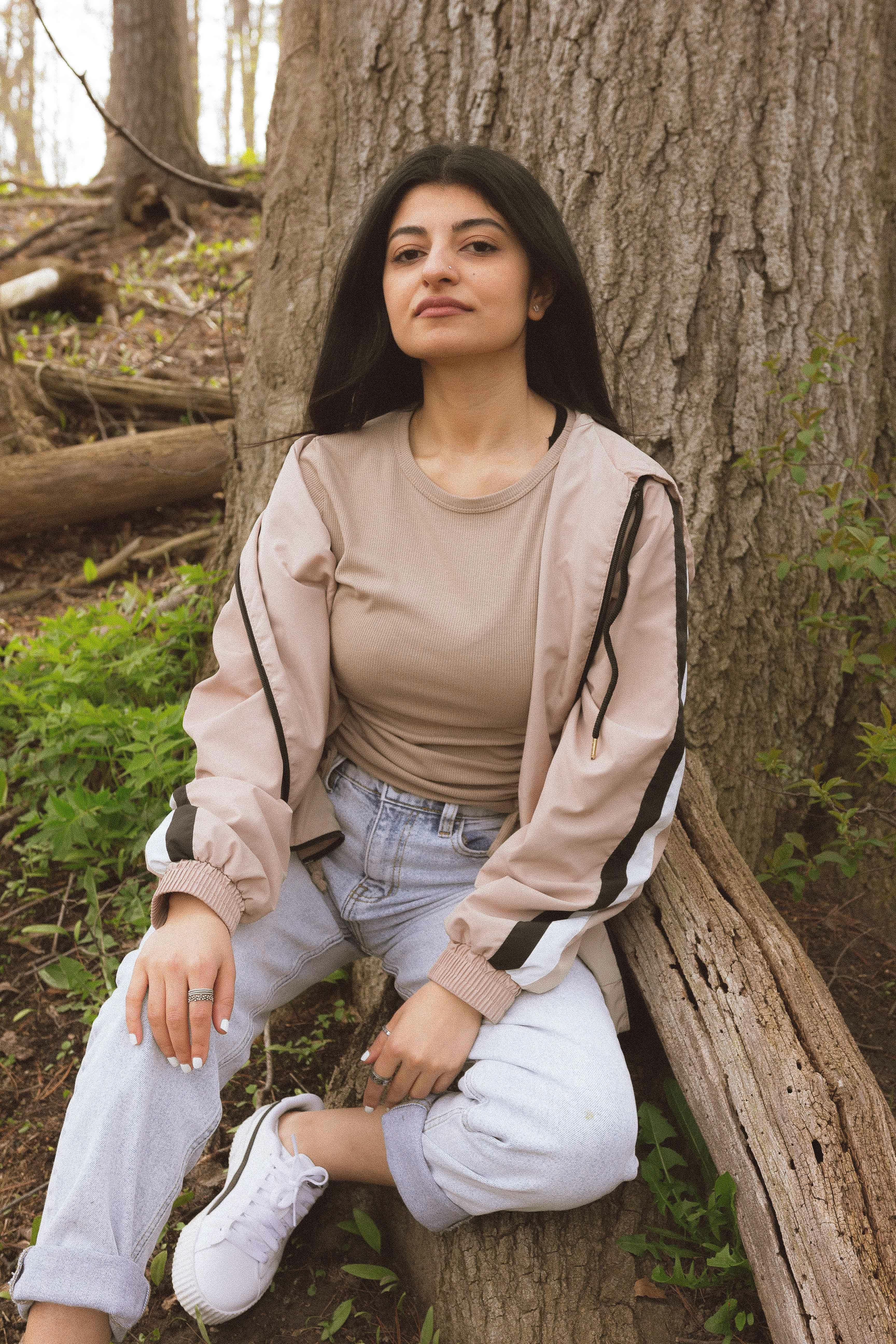 A Woman in Brown Jacket Sitting on Tree Roots · Free Stock Photo