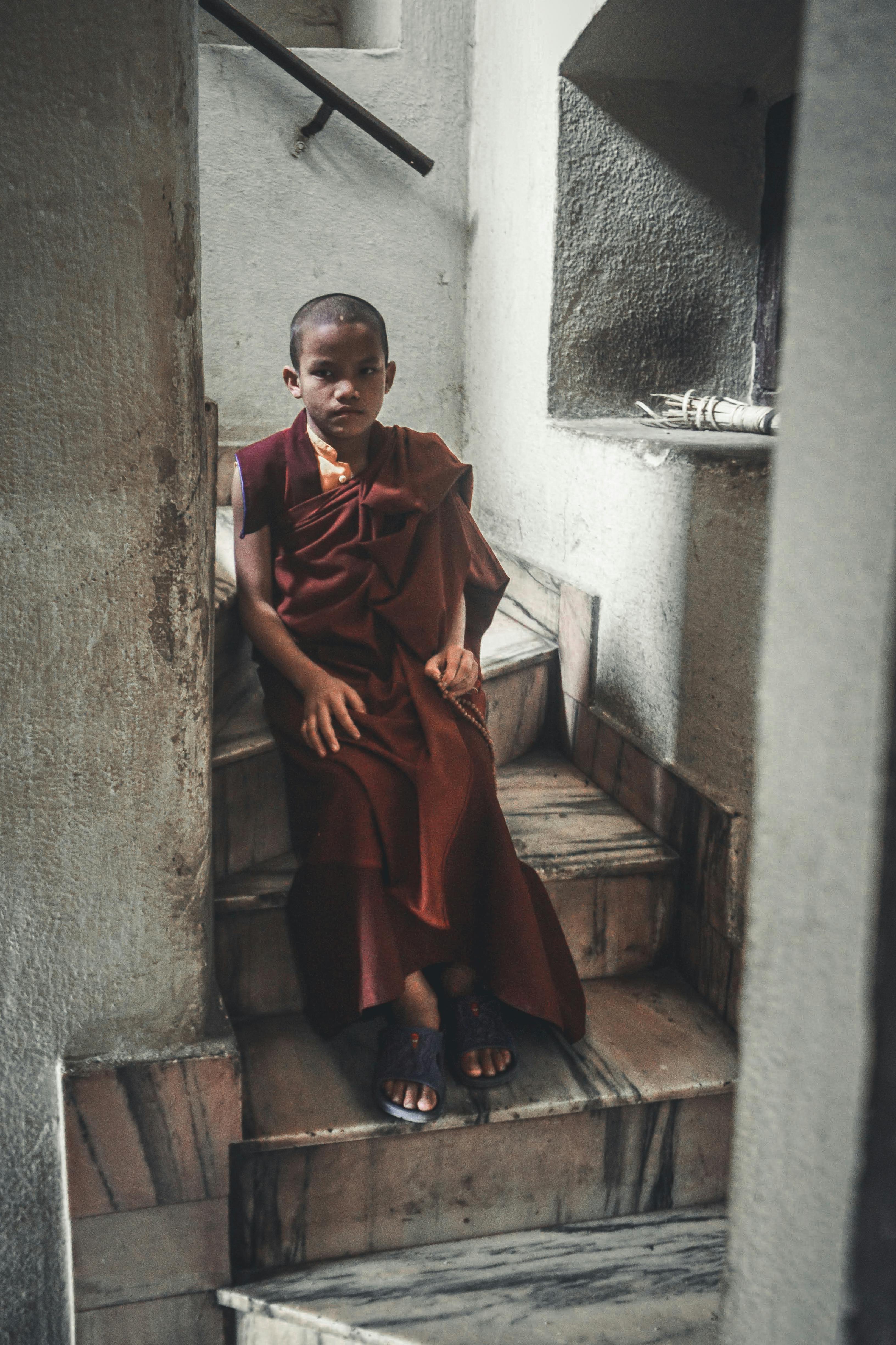 Little Boy in Monk Robes Leaning Against Pillar · Free Stock Photo