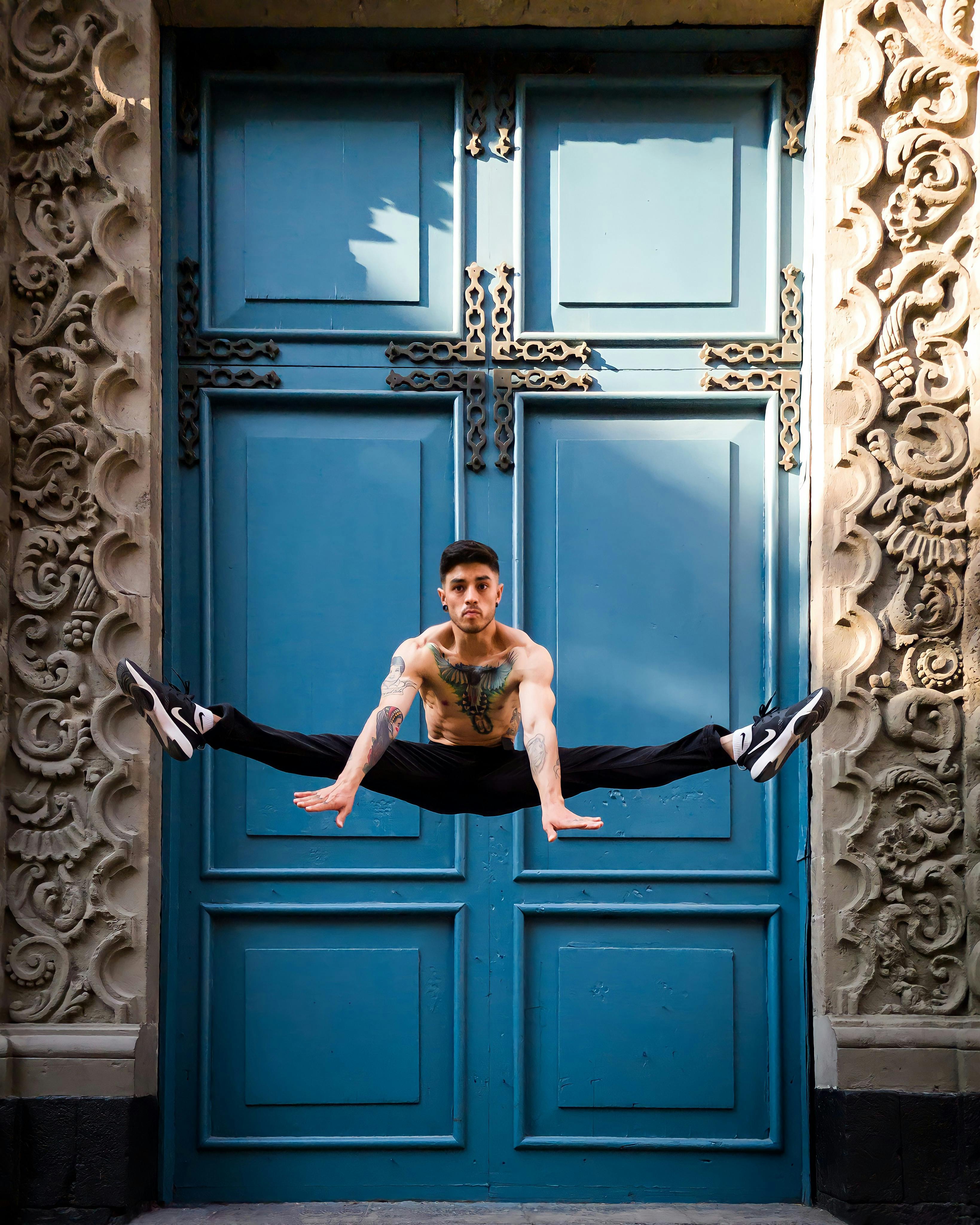 Split Jump of Topless Man Near Blue Door · Free Stock Photo