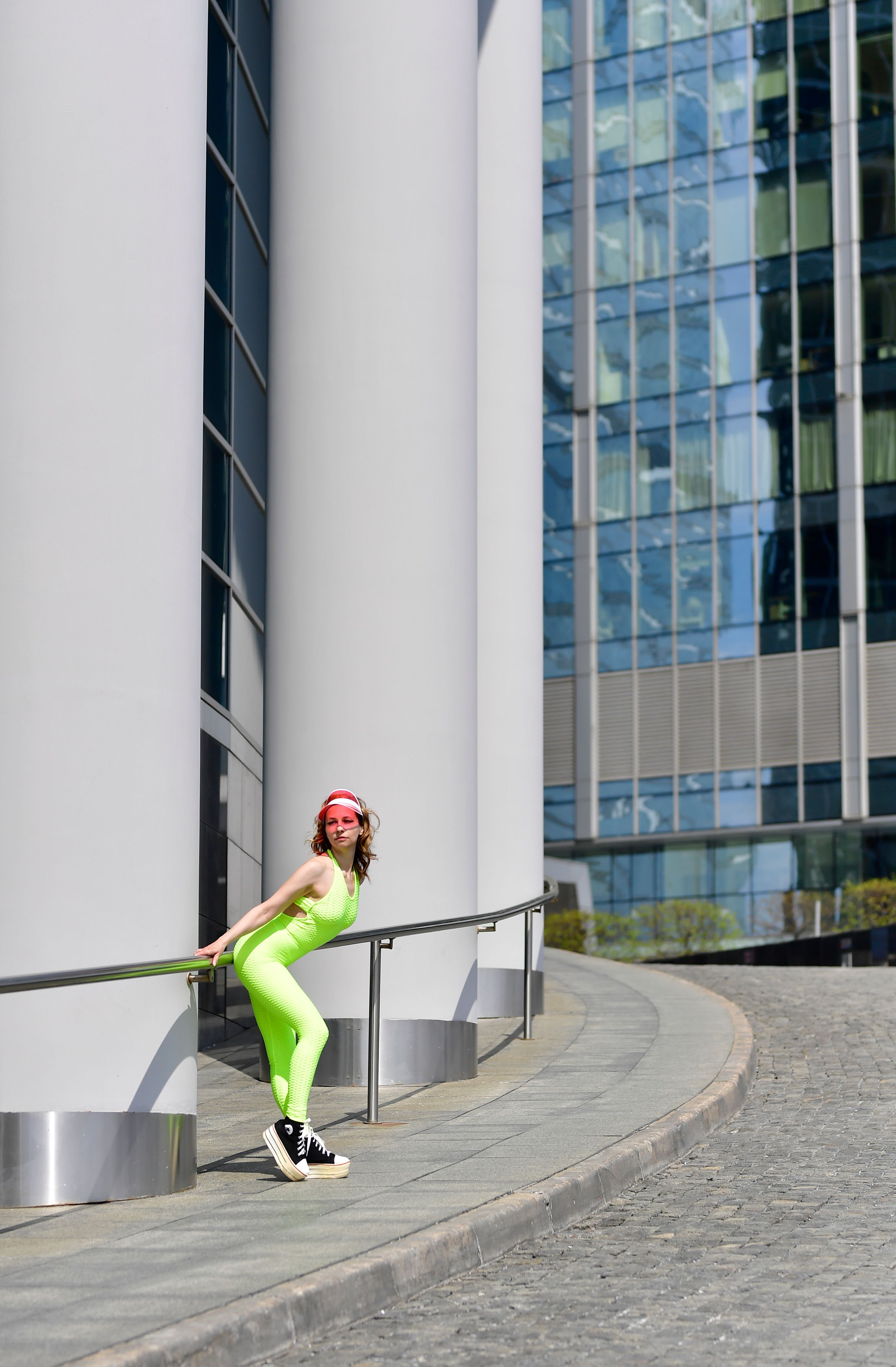 Woman Resting against Railing under Modern Building · Free Stock Photo