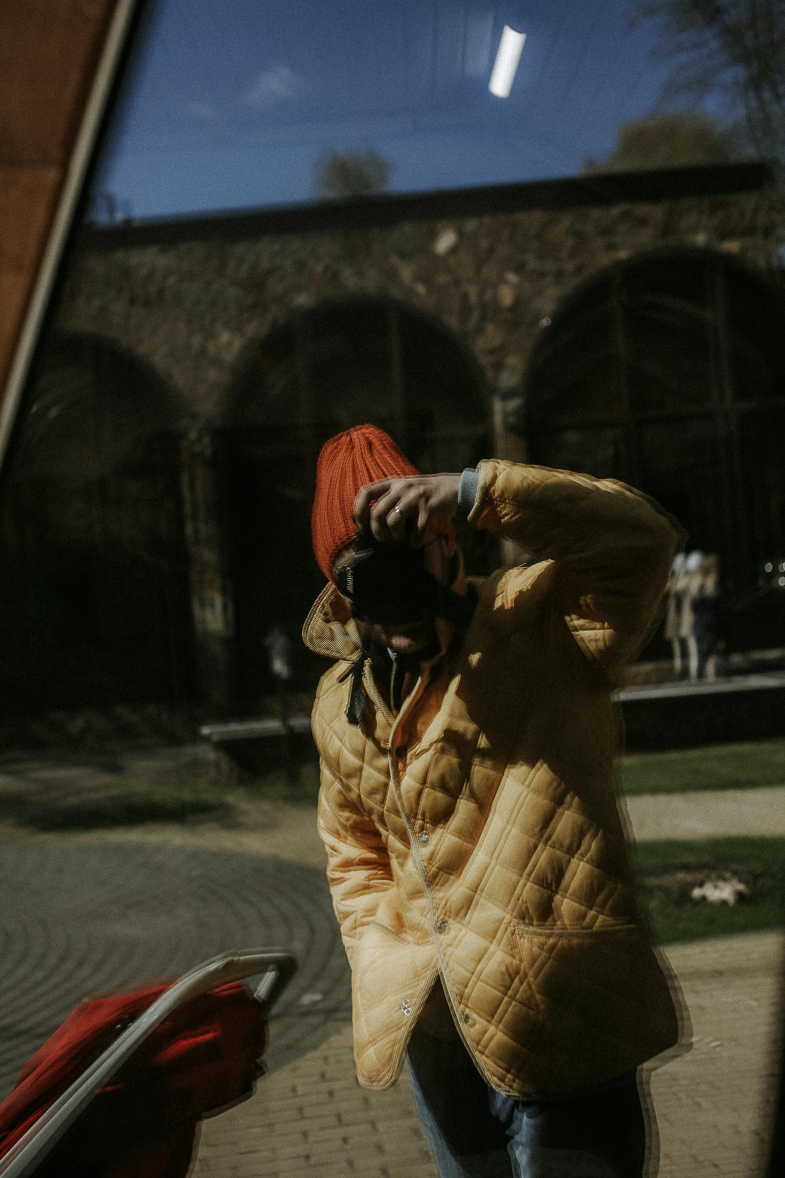 A Reflection of a Person in a Jacket and a Bonnet Taking a Picture of a ...