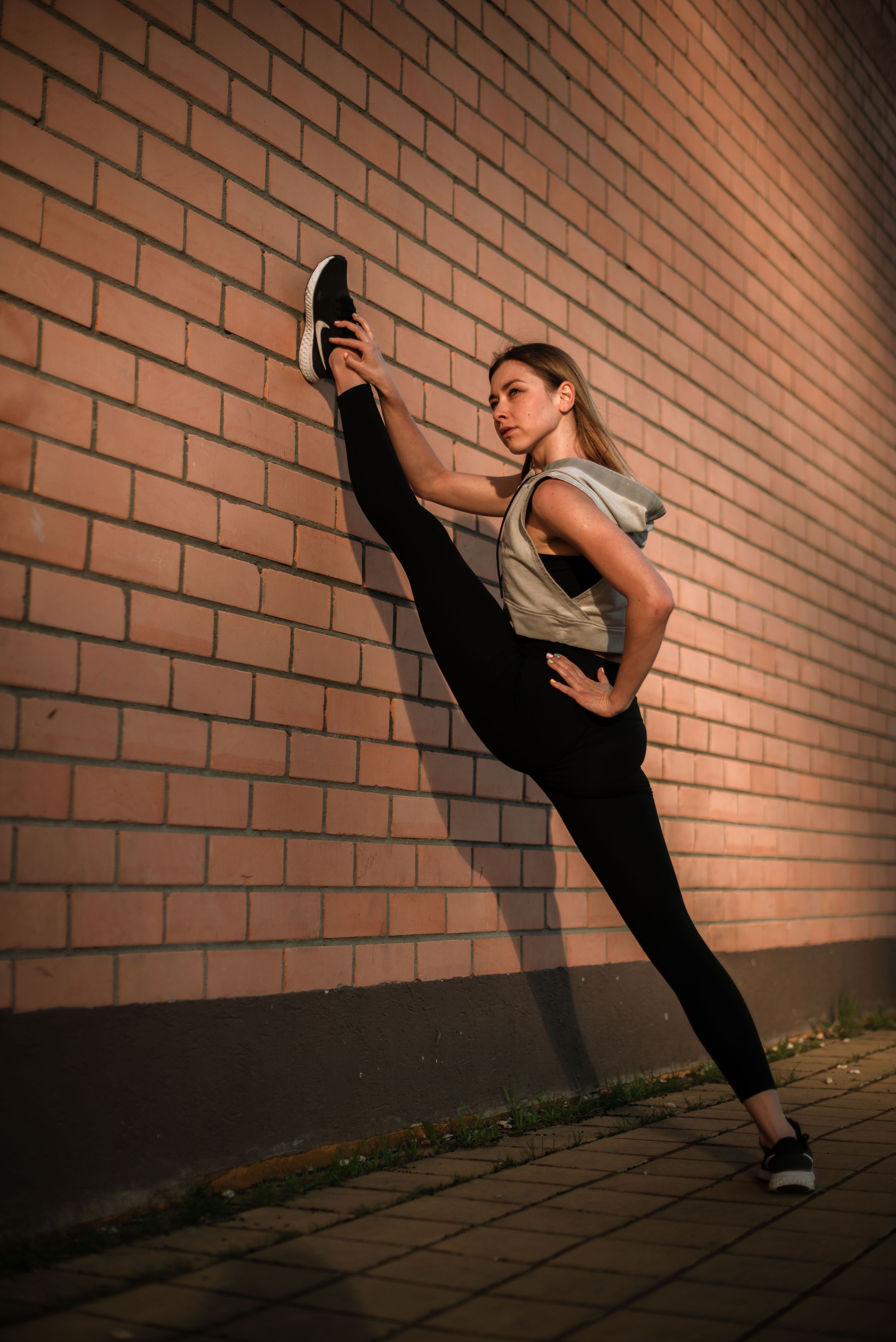 A Woman Stretching on a Brick Wall · Free Stock Photo