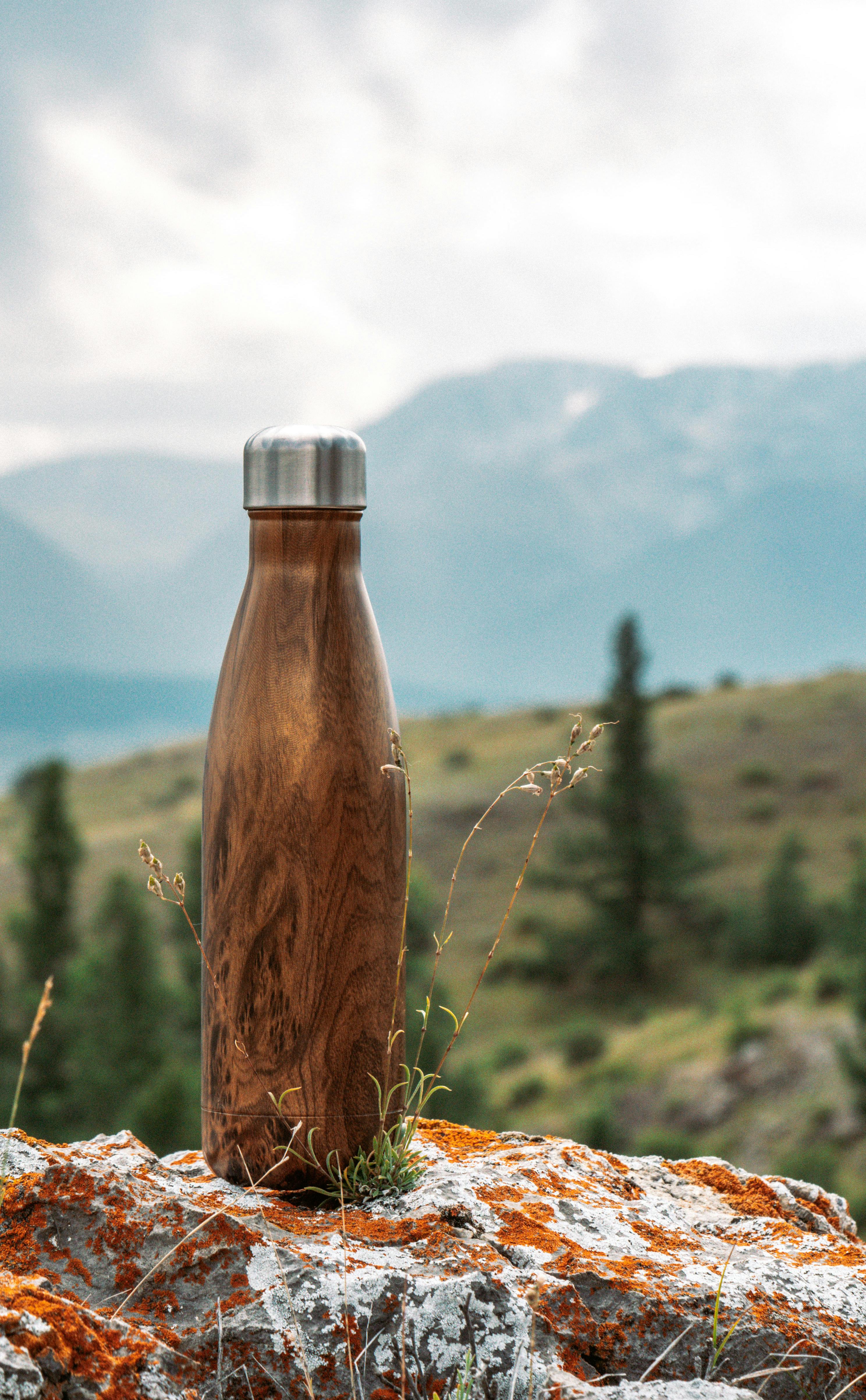 Wood Grain Thermal Water Bottle on Rock · Free Stock Photo