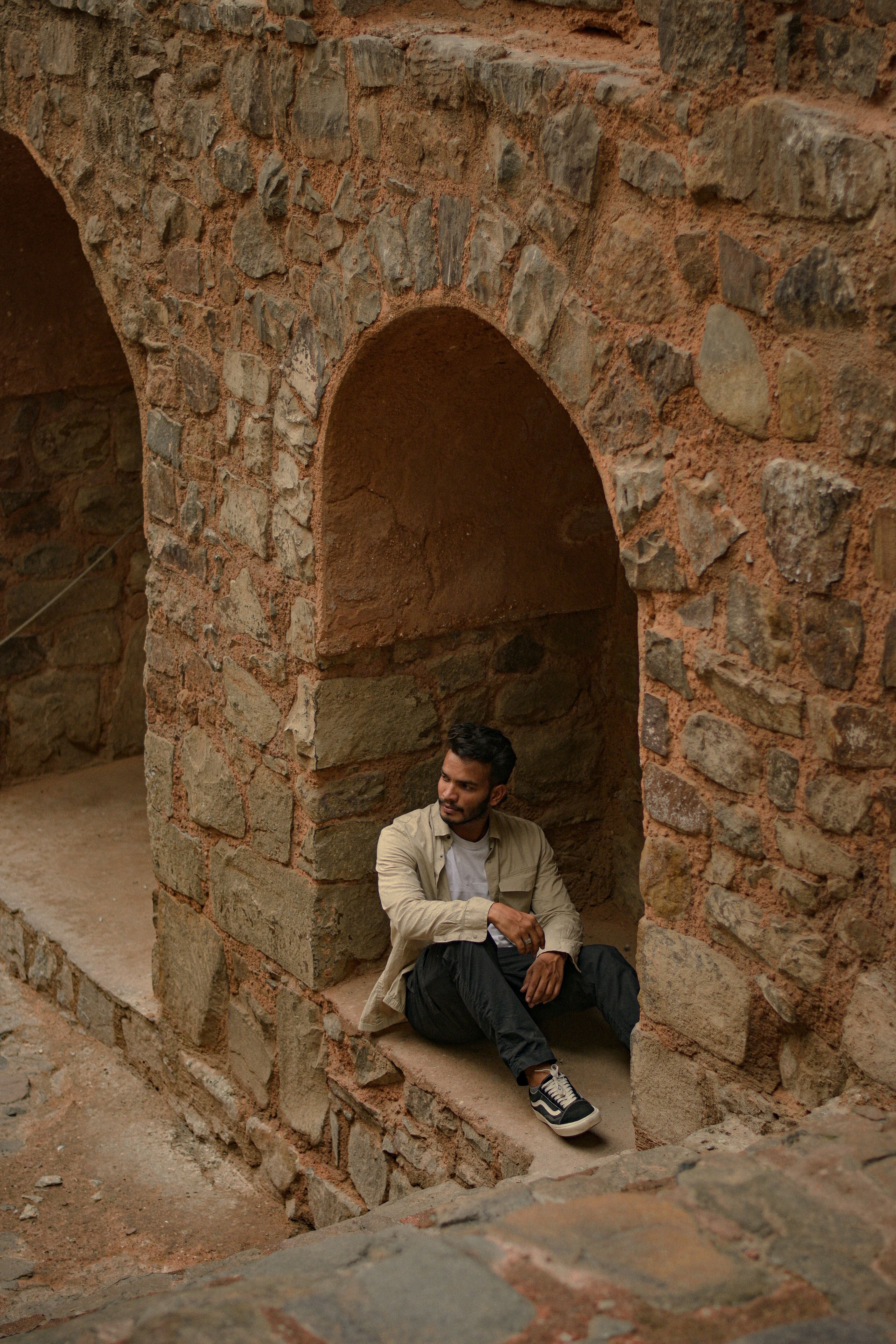 Woman Sitting under Arches in Wall · Free Stock Photo
