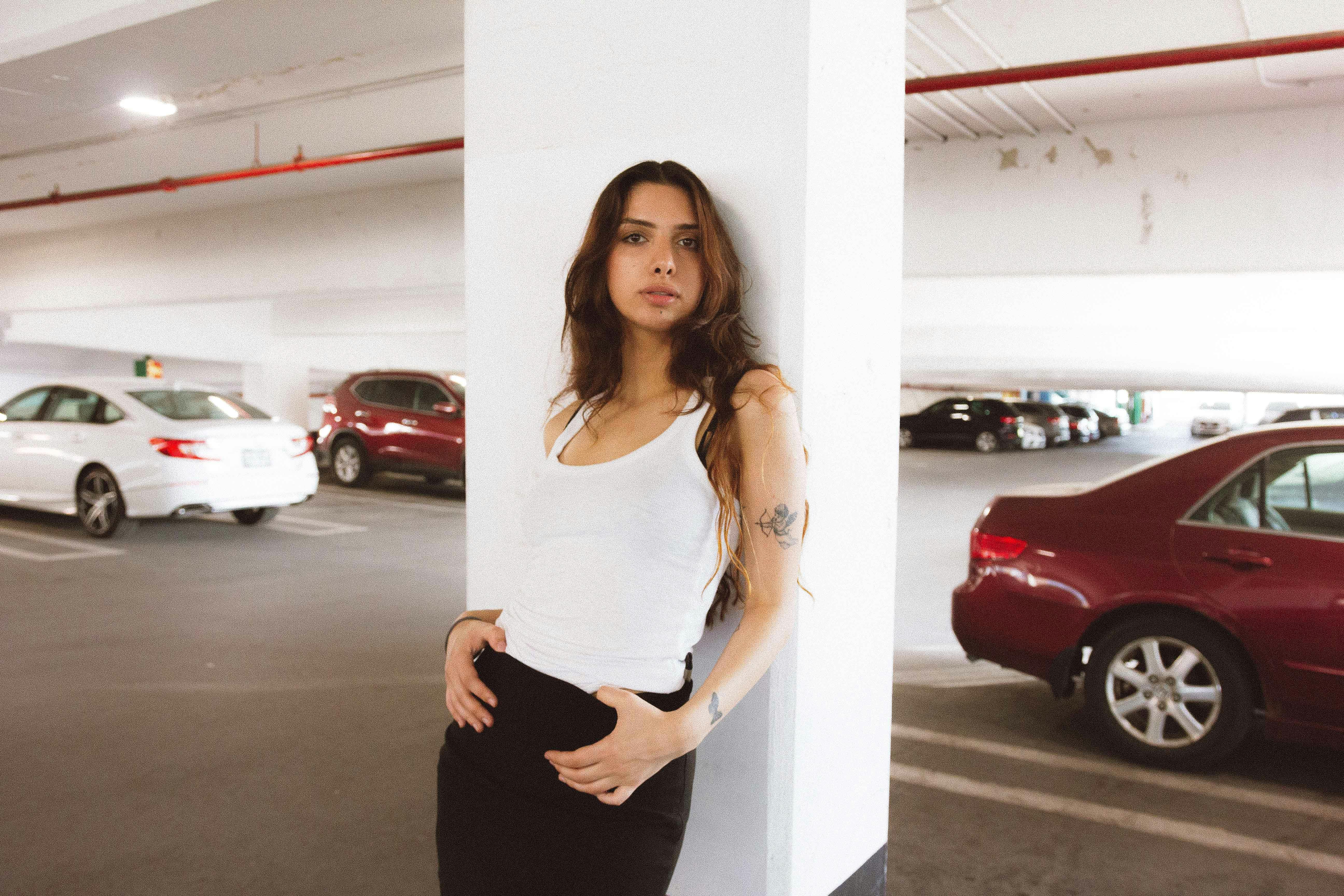 Beautiful Woman in White Tank Top leaning Column · Free Stock Photo