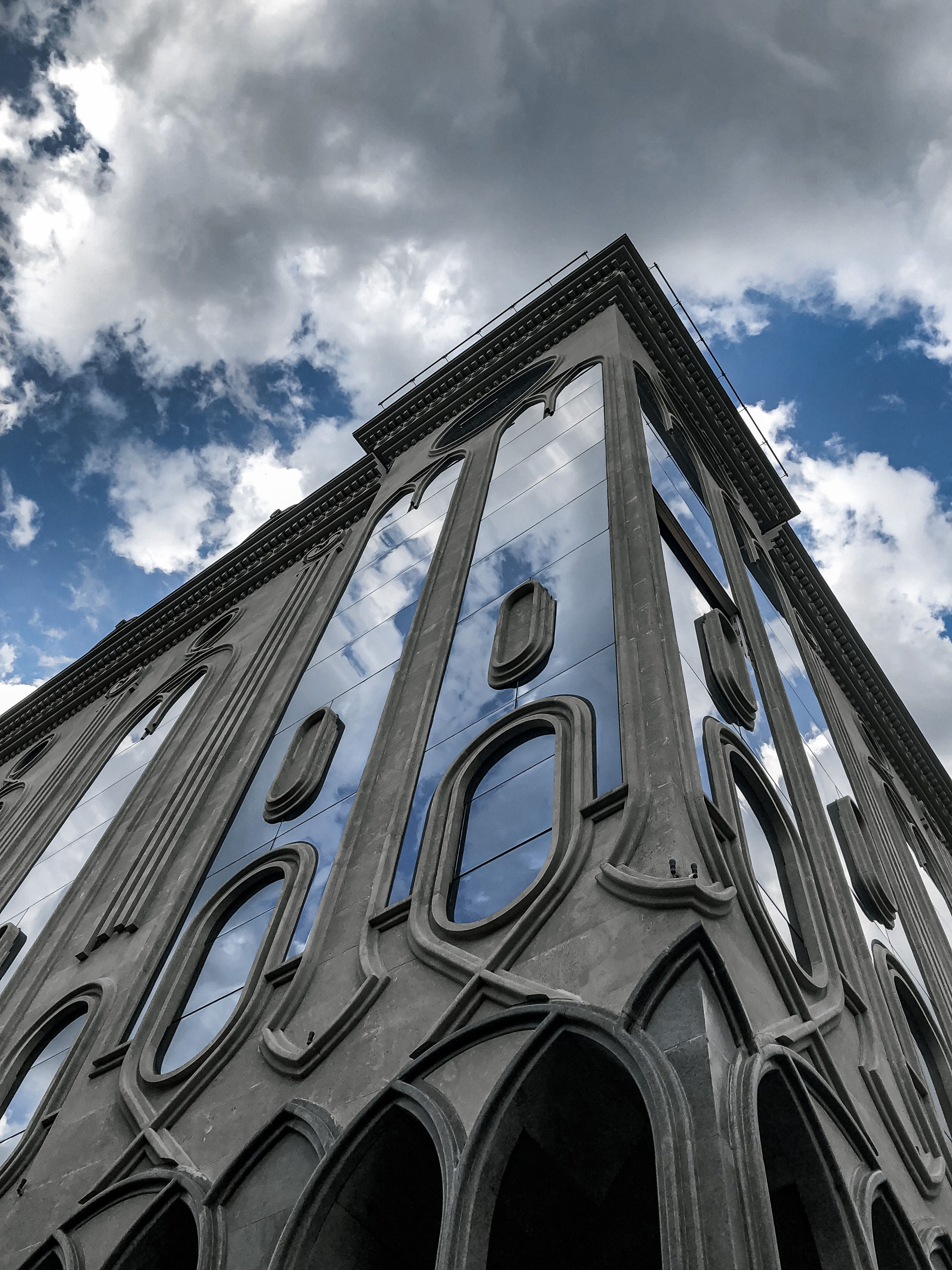 Low Angle Shot of a Glass Building Under White Clouds · Free Stock Photo