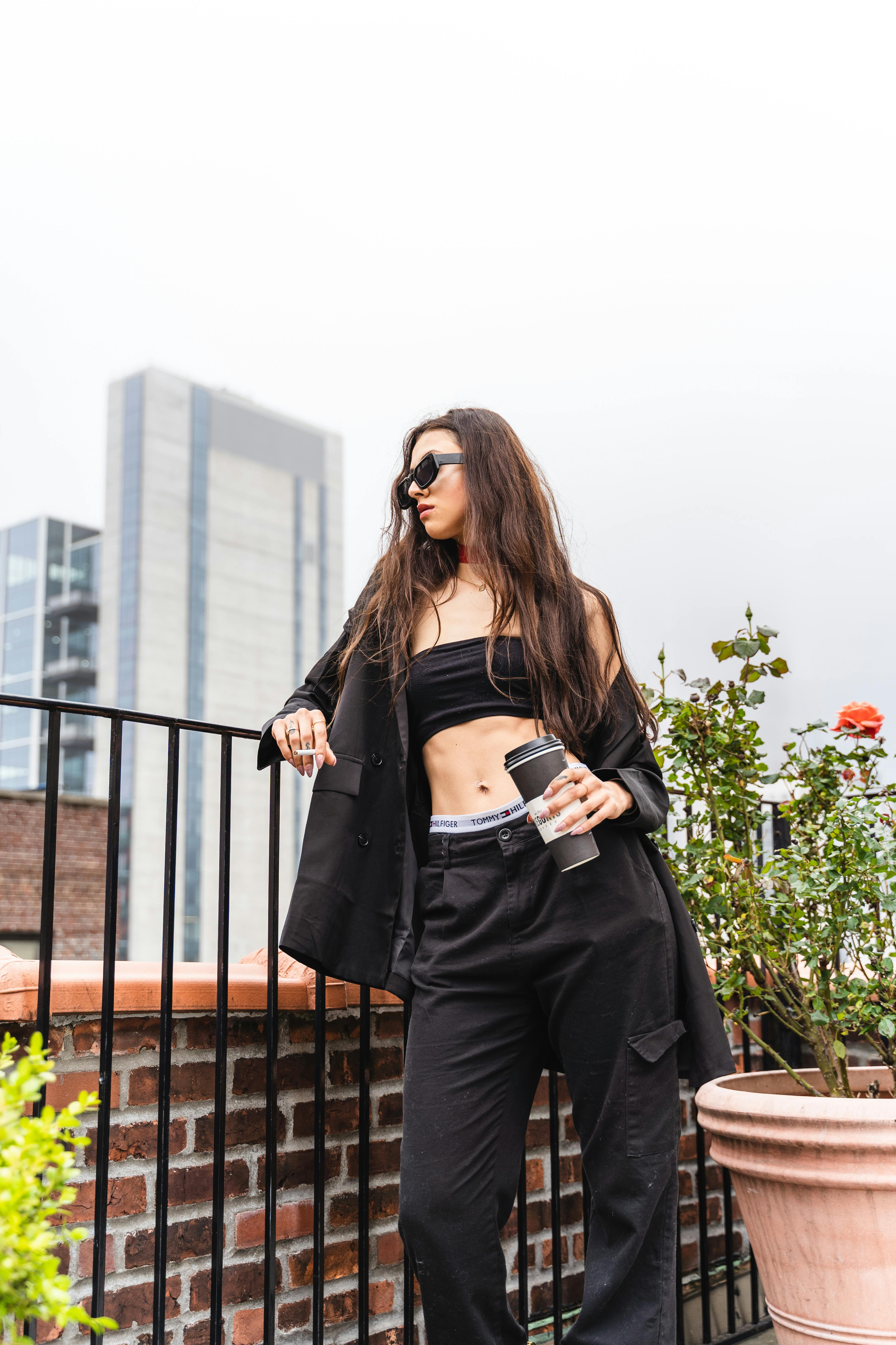 A Woman in Crop Top and Denim Pants Smoking a Cigarette · Free Stock Photo