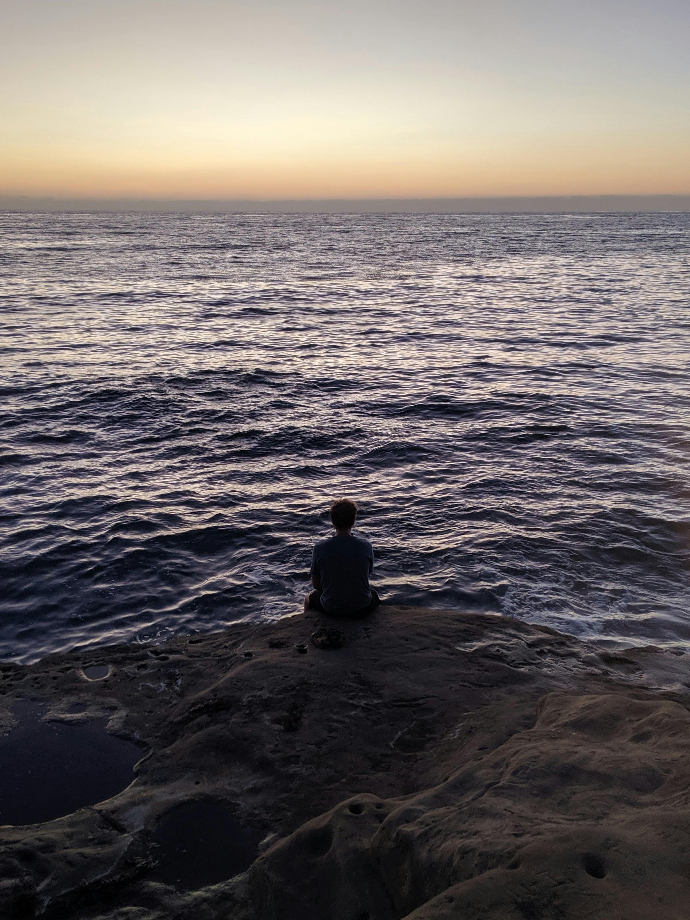 Person Standing in Sea at Sunset · Free Stock Photo