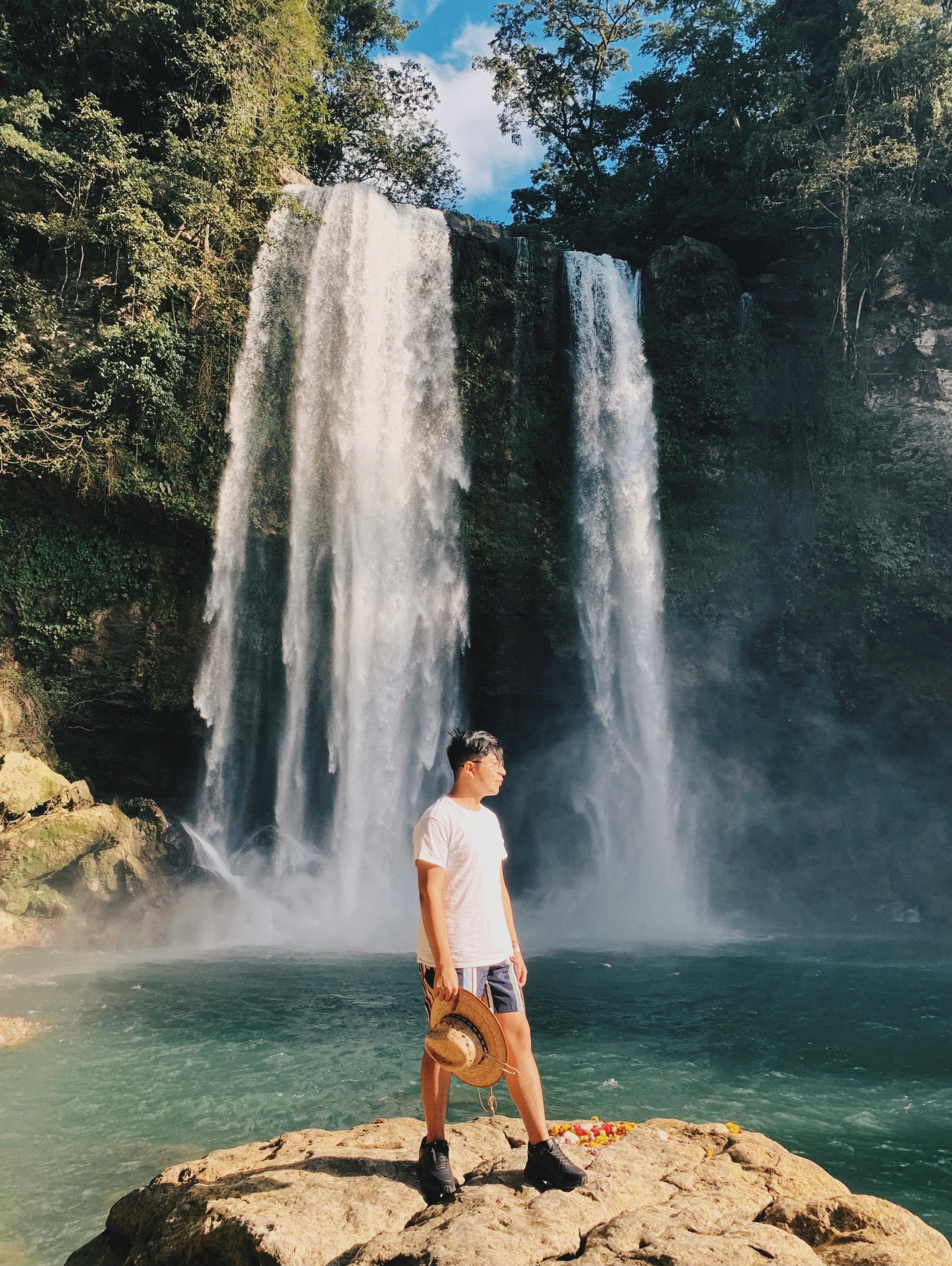 Photo of a Man Standing in front of a Waterfall and Pond · Free Stock Photo