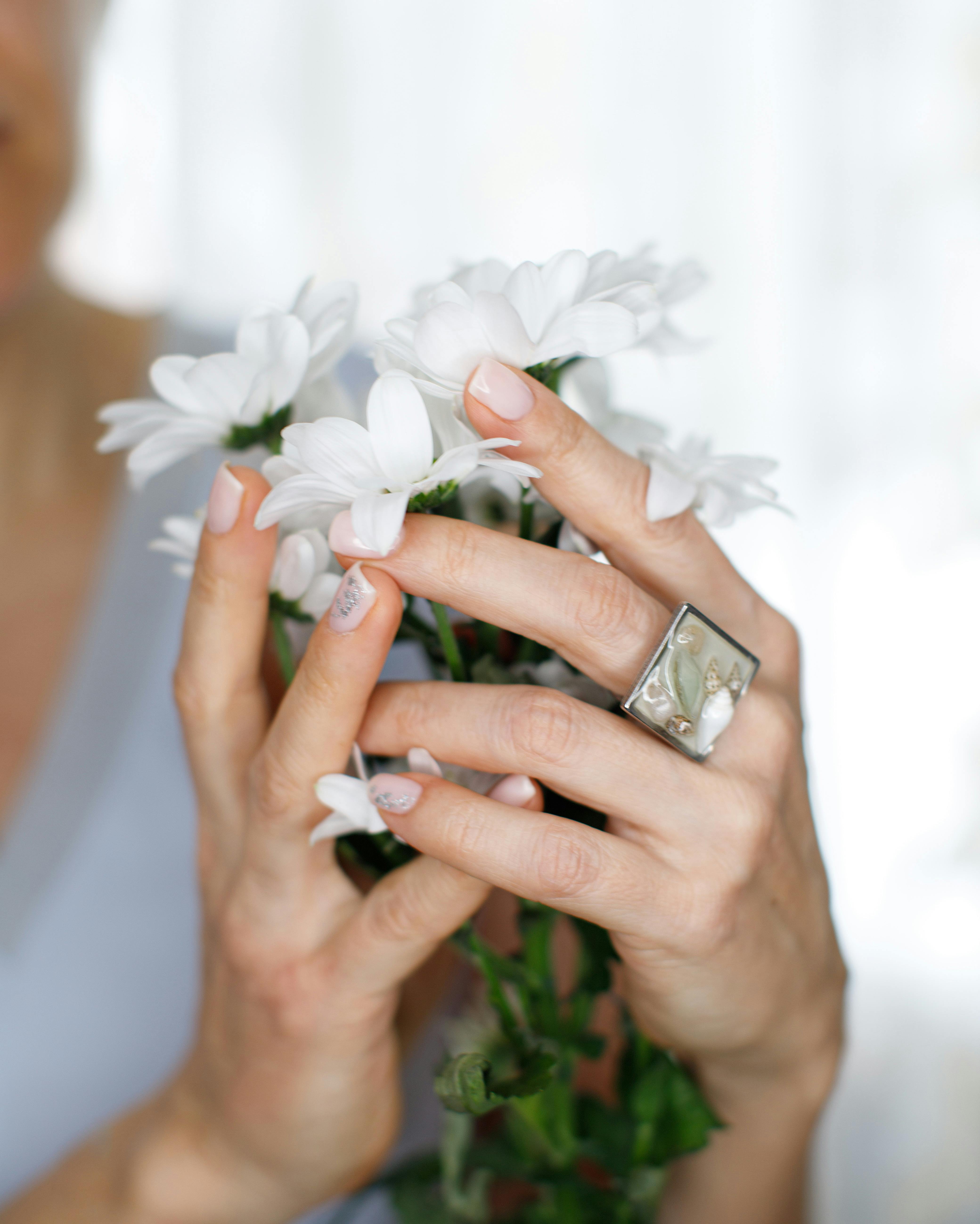 A Hand With Manicured Nails on White Textile · Free Stock Photo