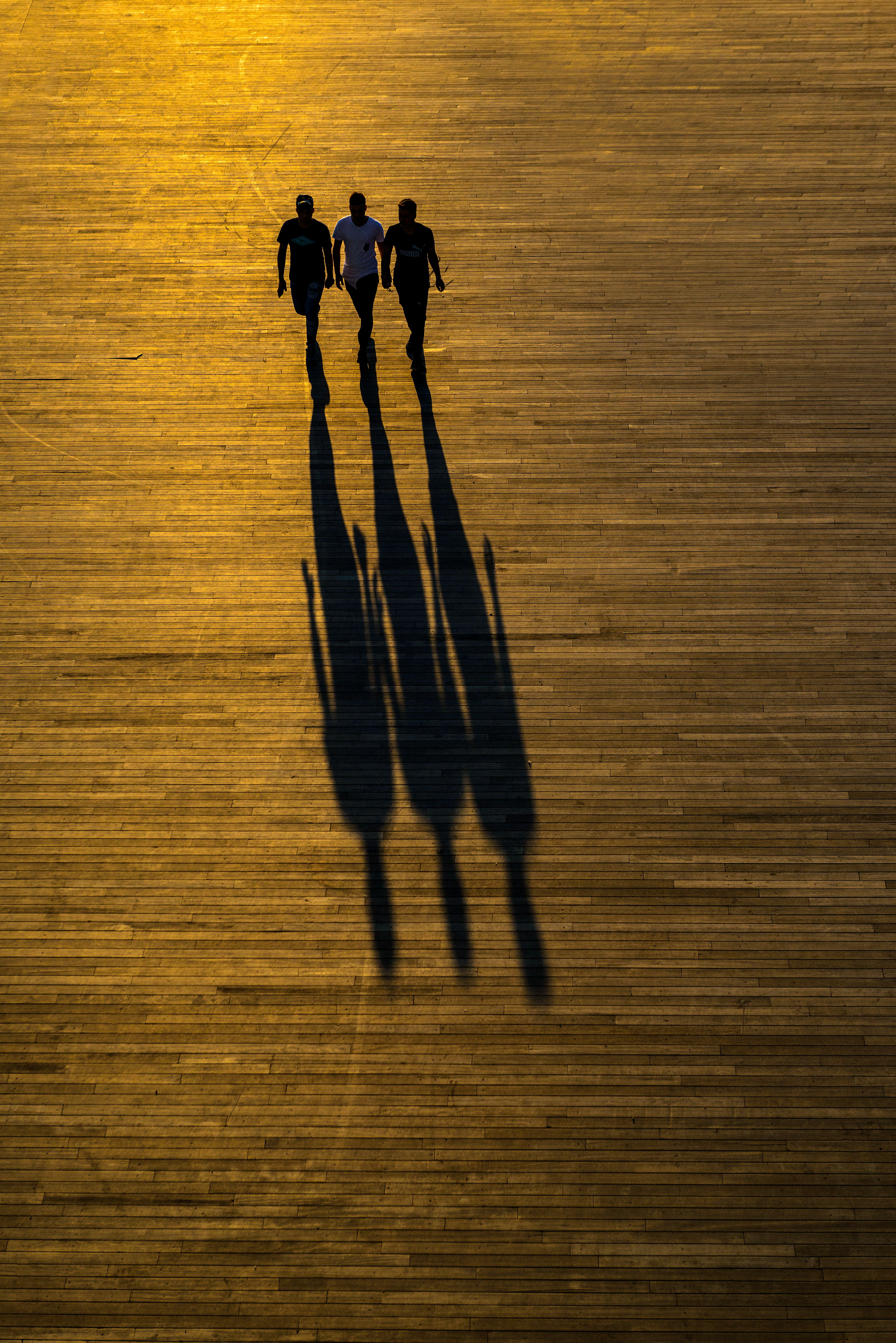 Three People Casting Long Shadows · Free Stock Photo