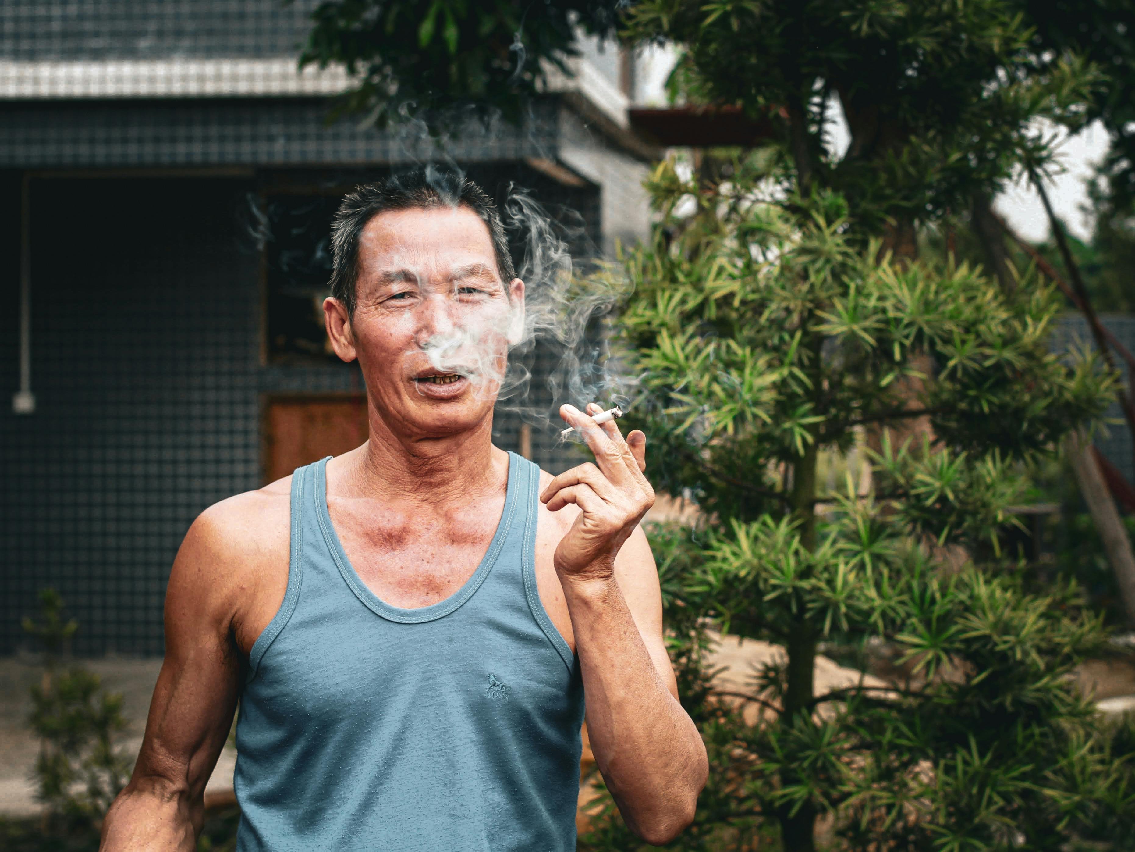 Man Smoking Cigarette in Workshop · Free Stock Photo