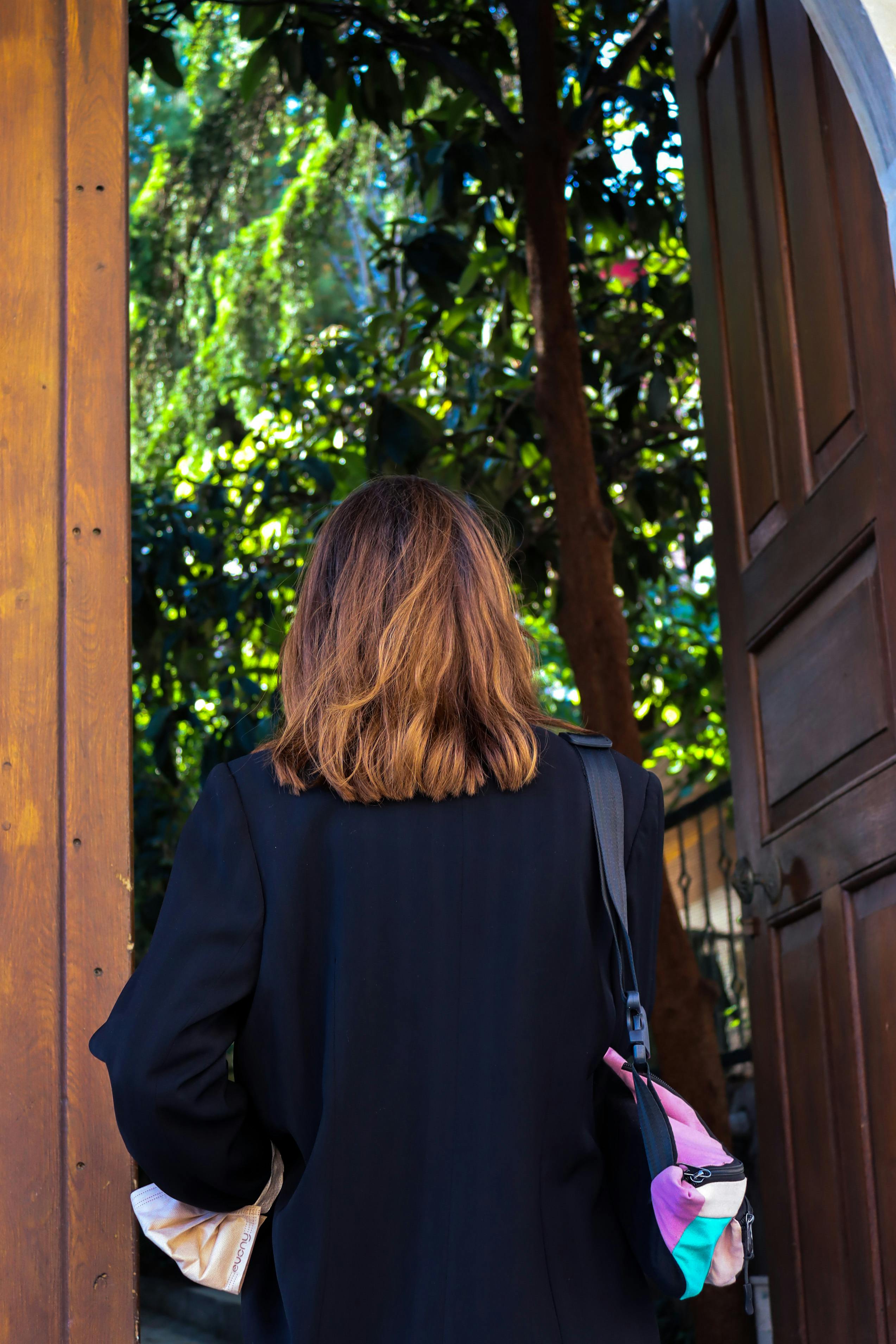 Back View of a Woman Entering a Wooden Door · Free Stock Photo