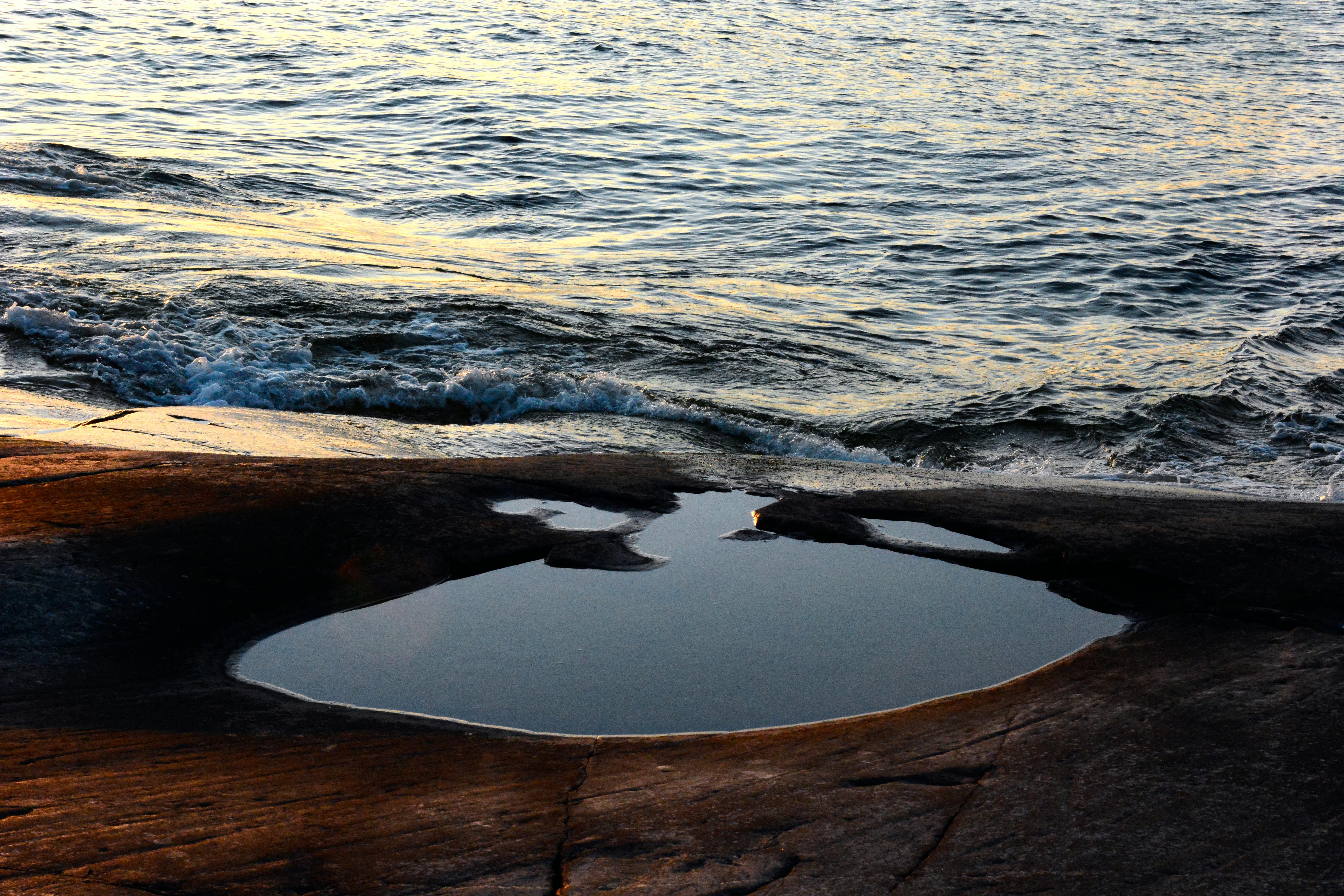 A Puddle on Brown Surface Beside Flowing Body of Water · Free Stock Photo