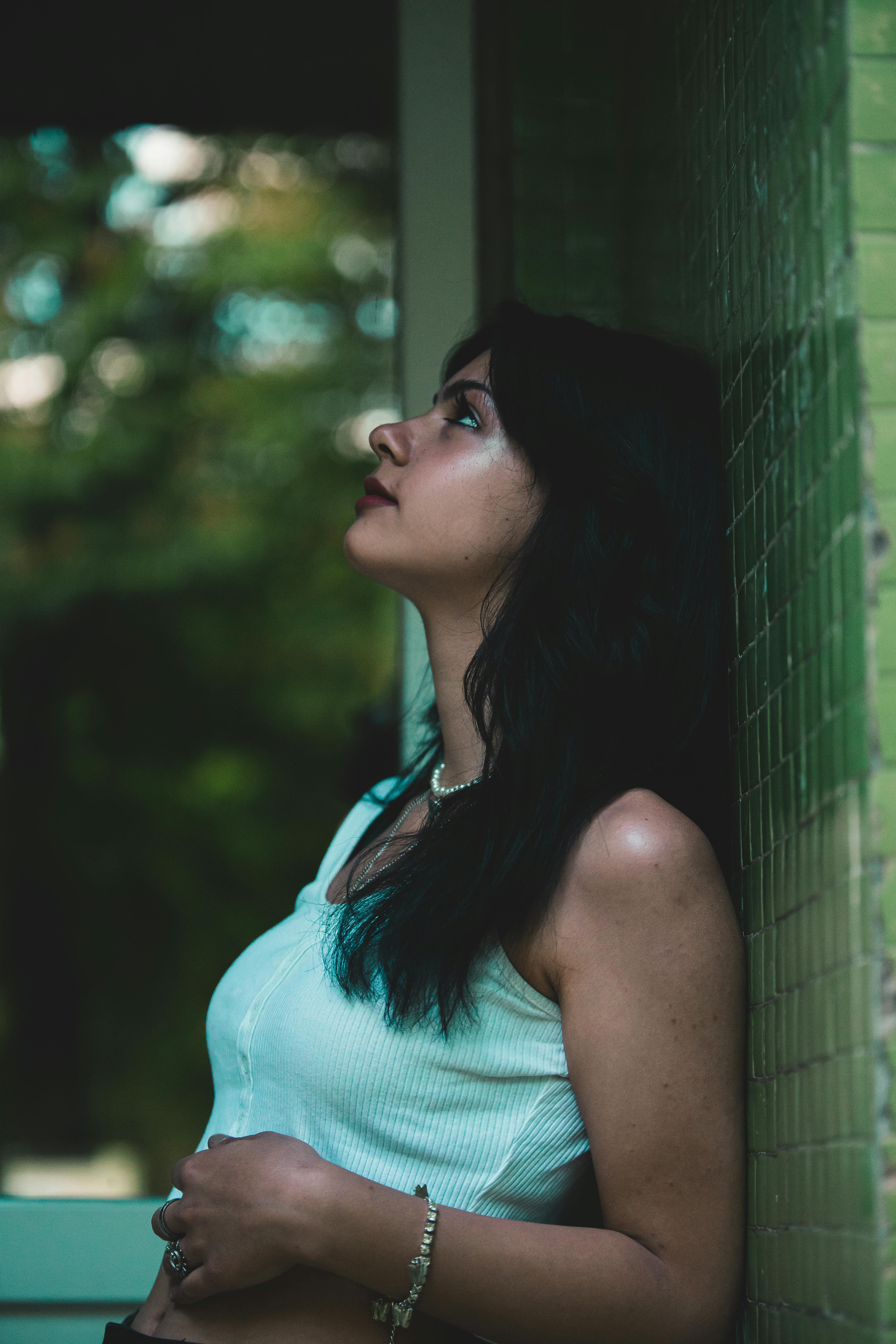 Woman in White Tank Top Leaning on Green Wall · Free Stock Photo
