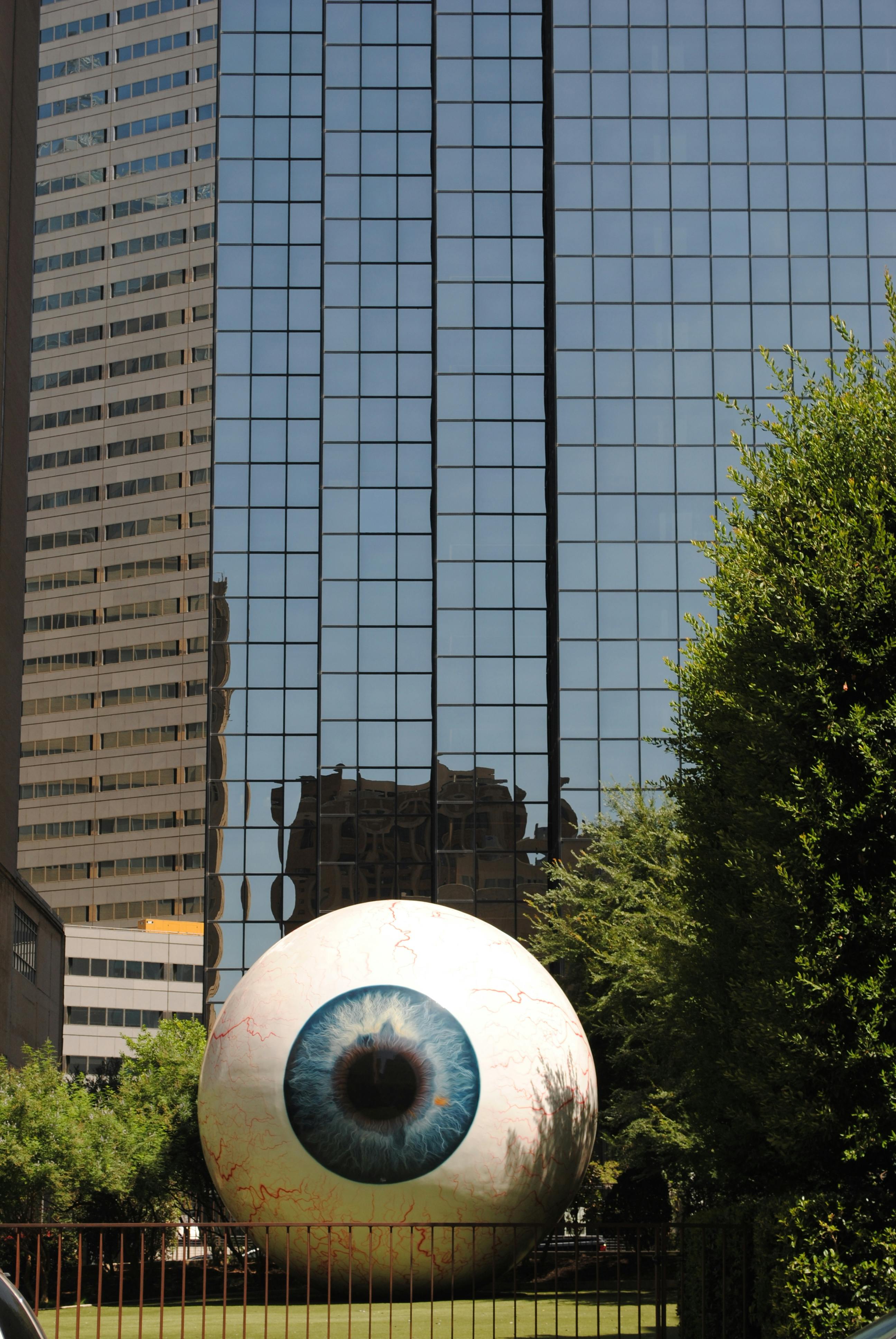 Modern Eye Sculpture near Glass Skyscraper · Free Stock Photo