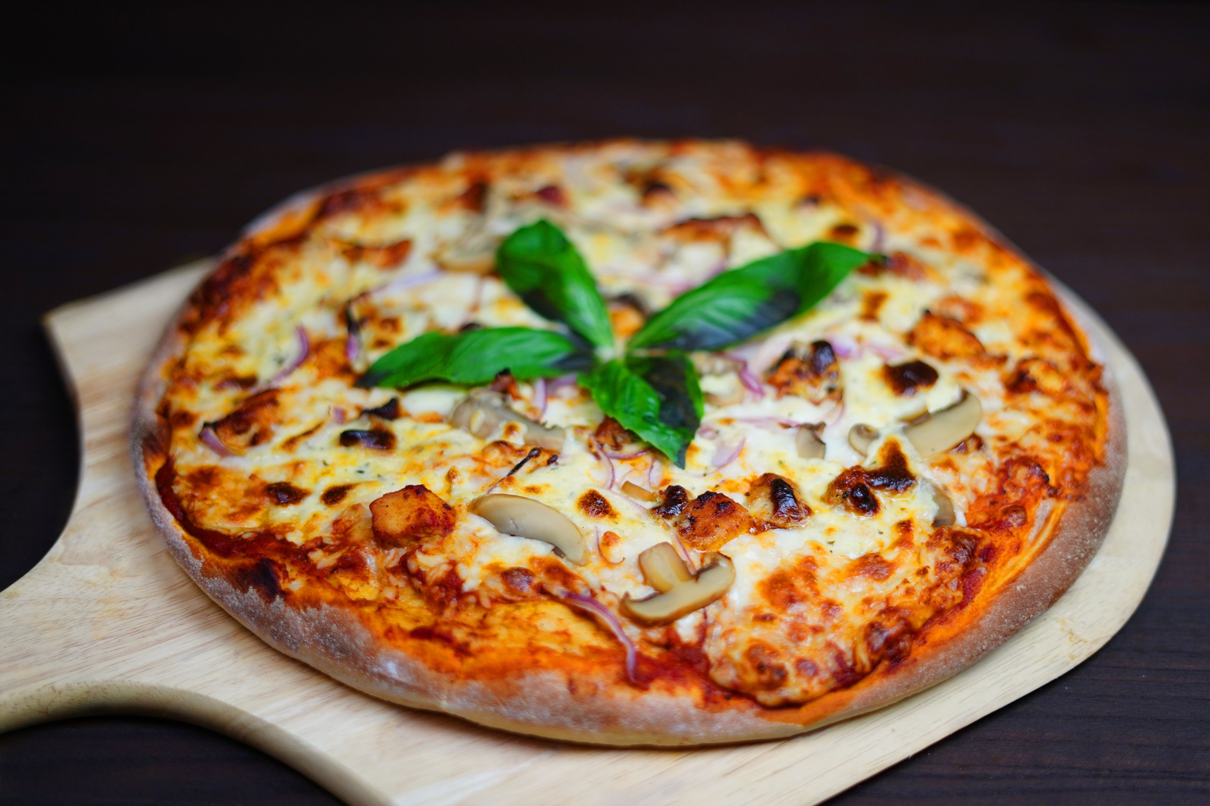 Pizza with Green Leaves on Wooden Board · Free Stock Photo