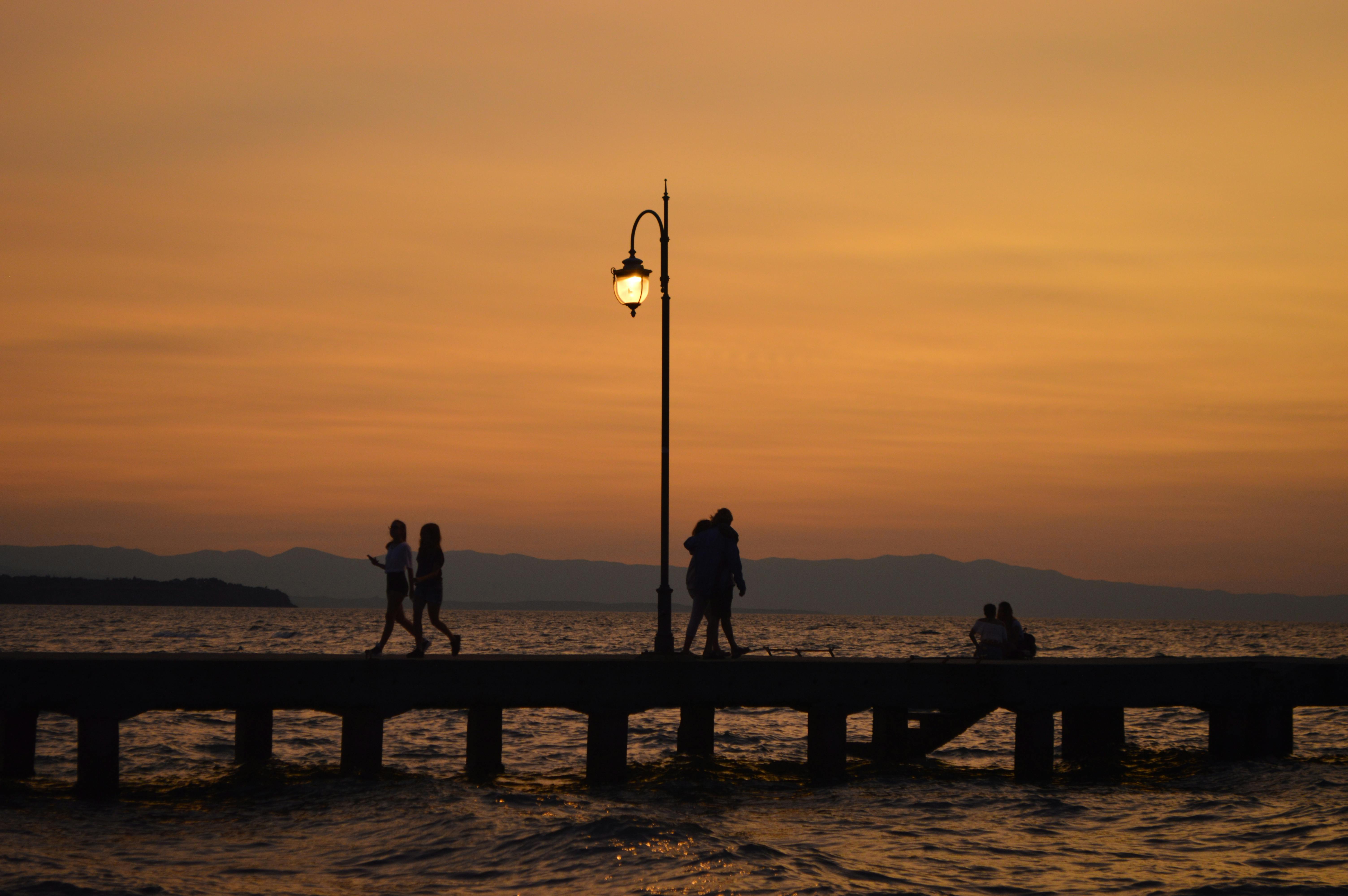 Silhouettes of People Walking Near the Sea · Free Stock Photo