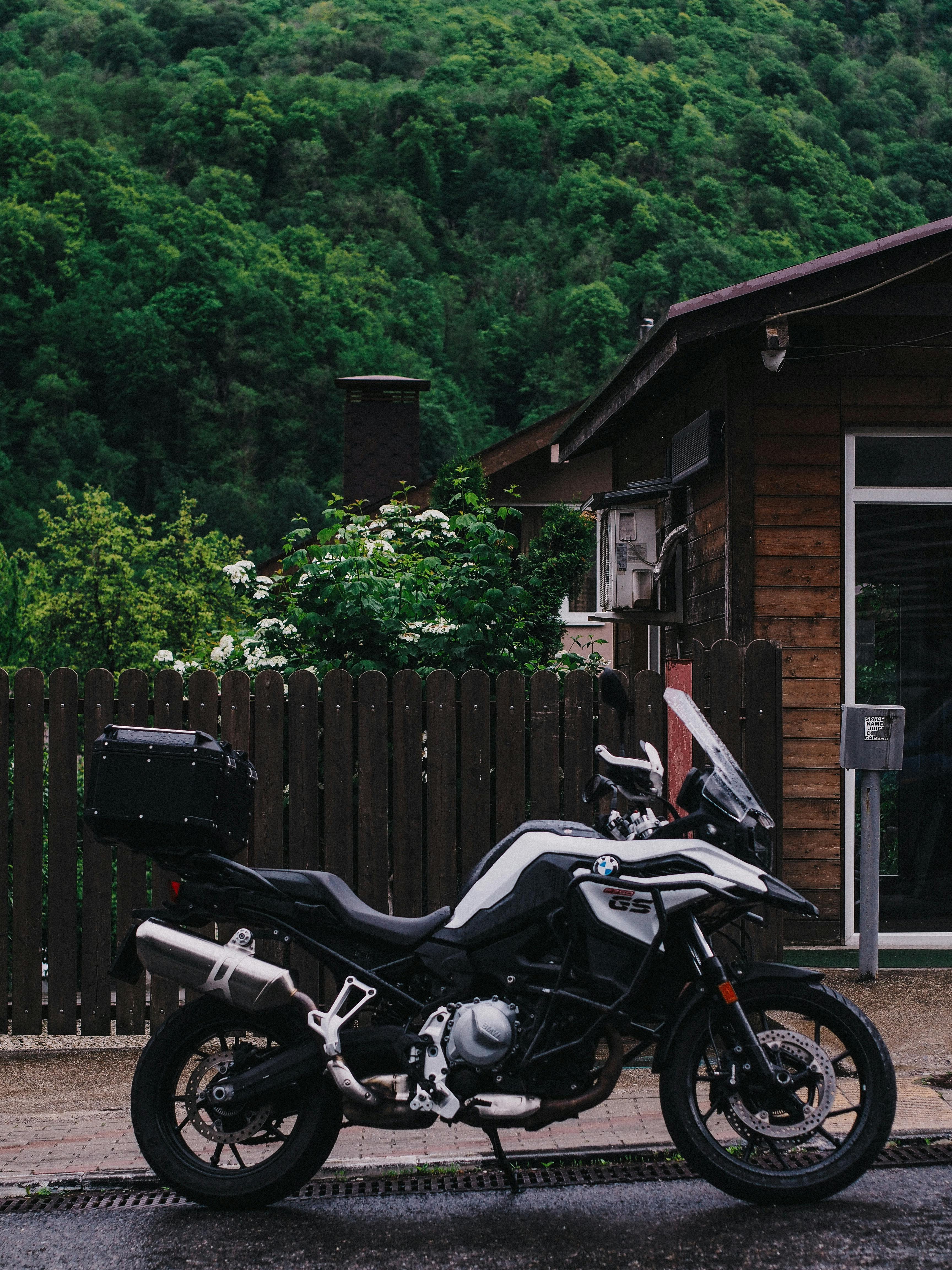 Black and White Motorcycle Parked Beside Wooden House · Free Stock Photo