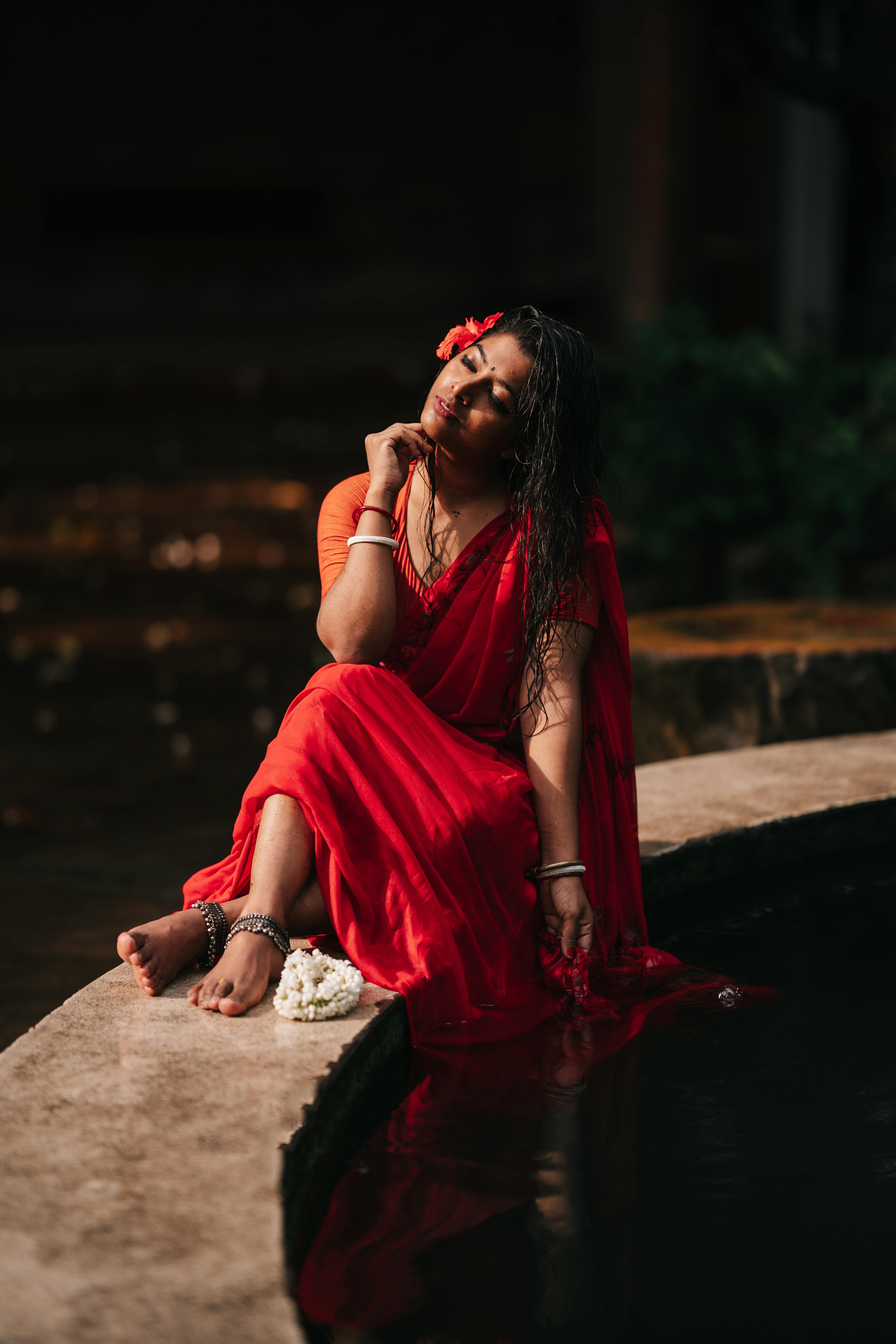 A Woman in Red Saree Sitting on a Concrete Bench · Free Stock Photo