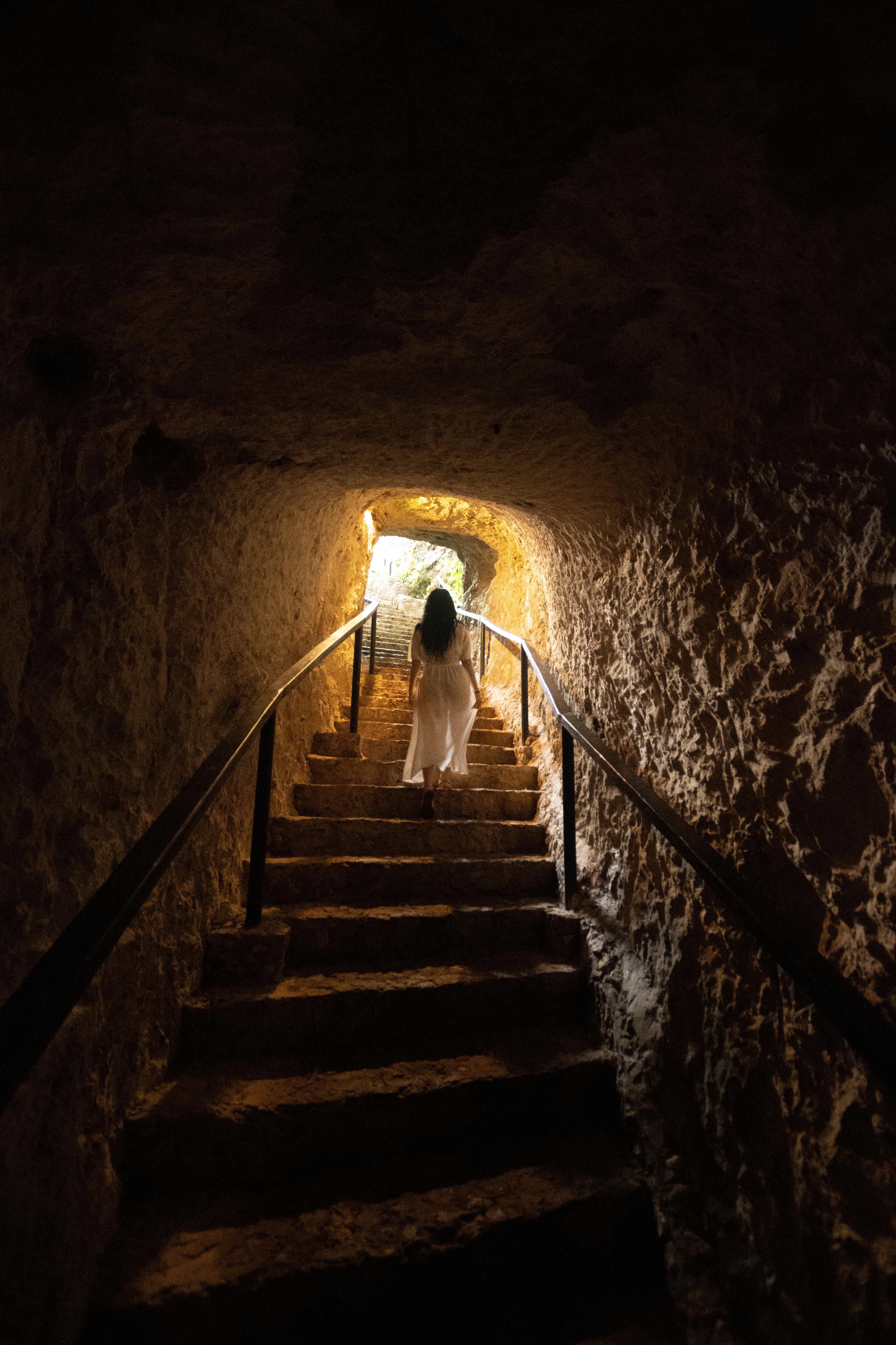 Woman in White Dress Walking Up the Stairs Inside a Cave · Free Stock Photo