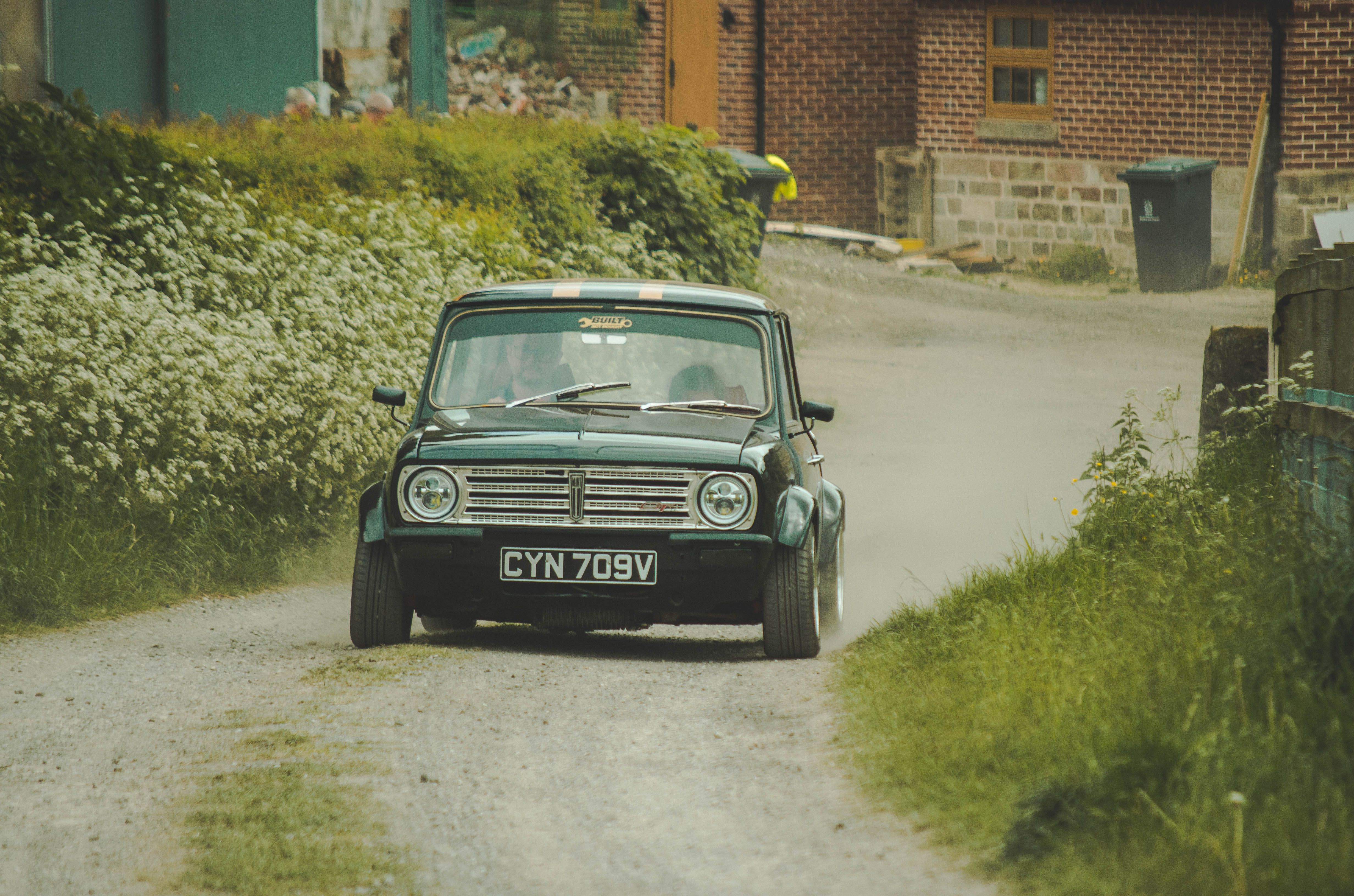 A Black Car Moving on the Road Between Green Grass Field · Free Stock Photo